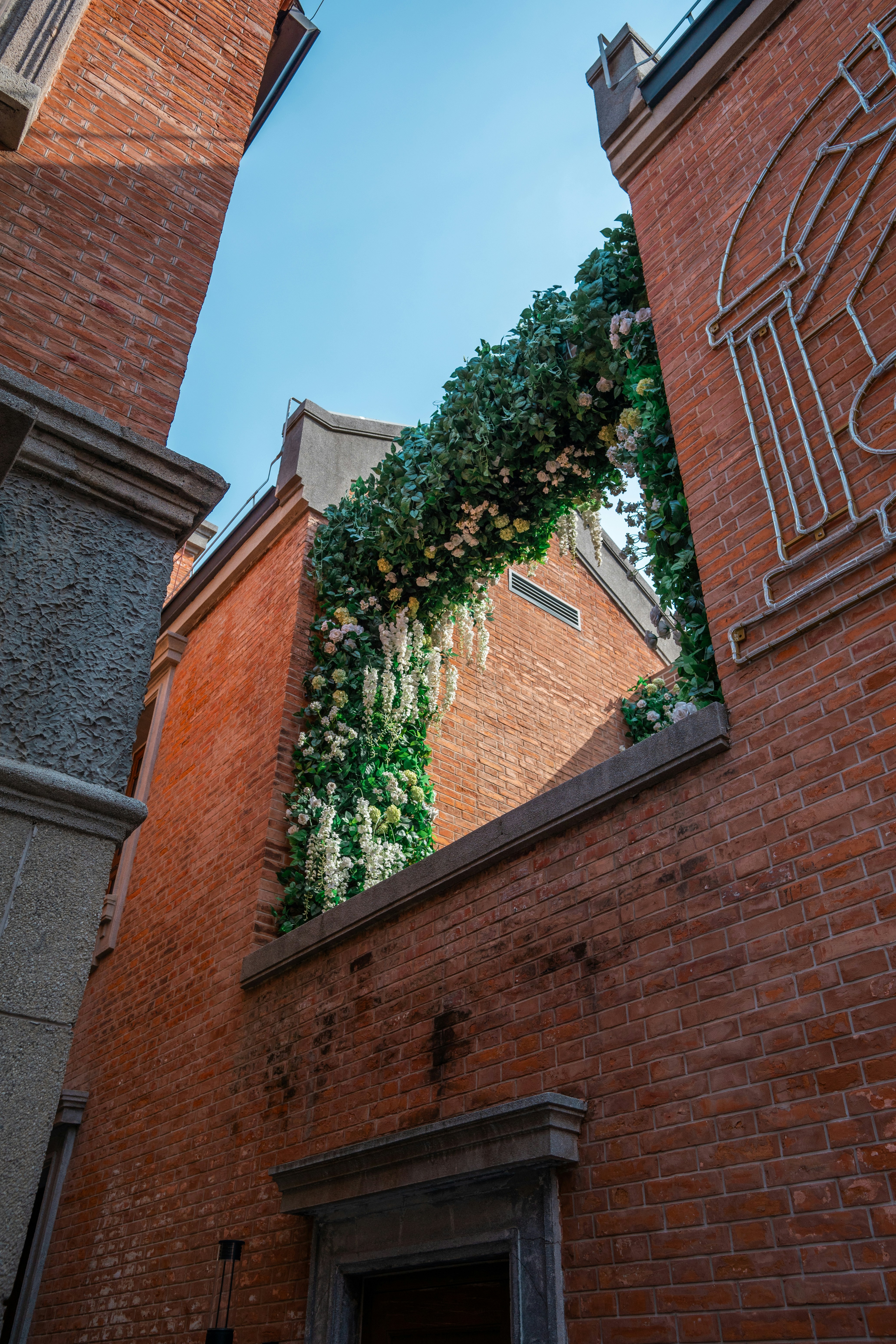 Floral Archway Between Brick Walls under Bright Blue Sky