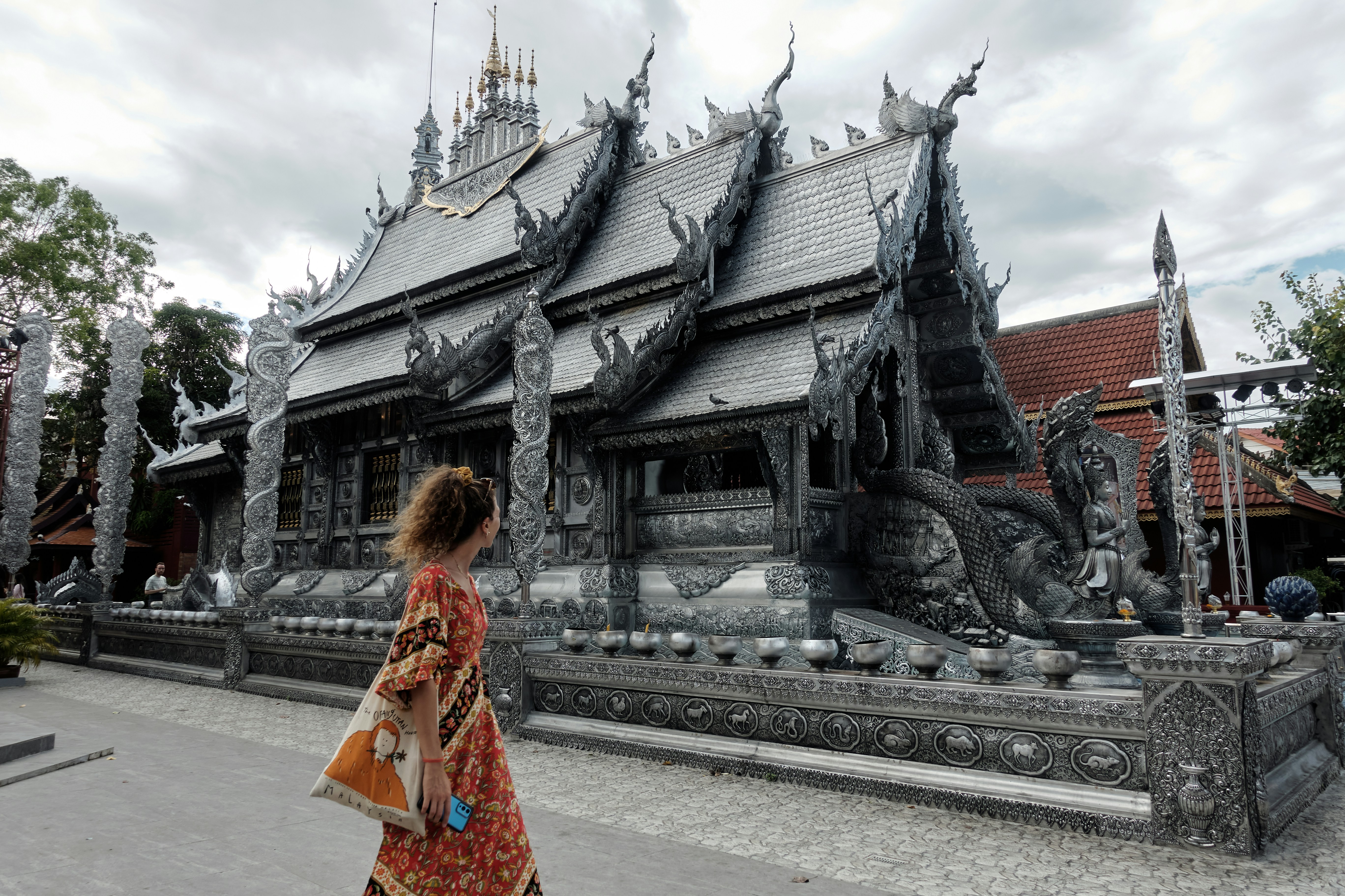 Traveler in a patterned dress approaches a sculpted temple dragon