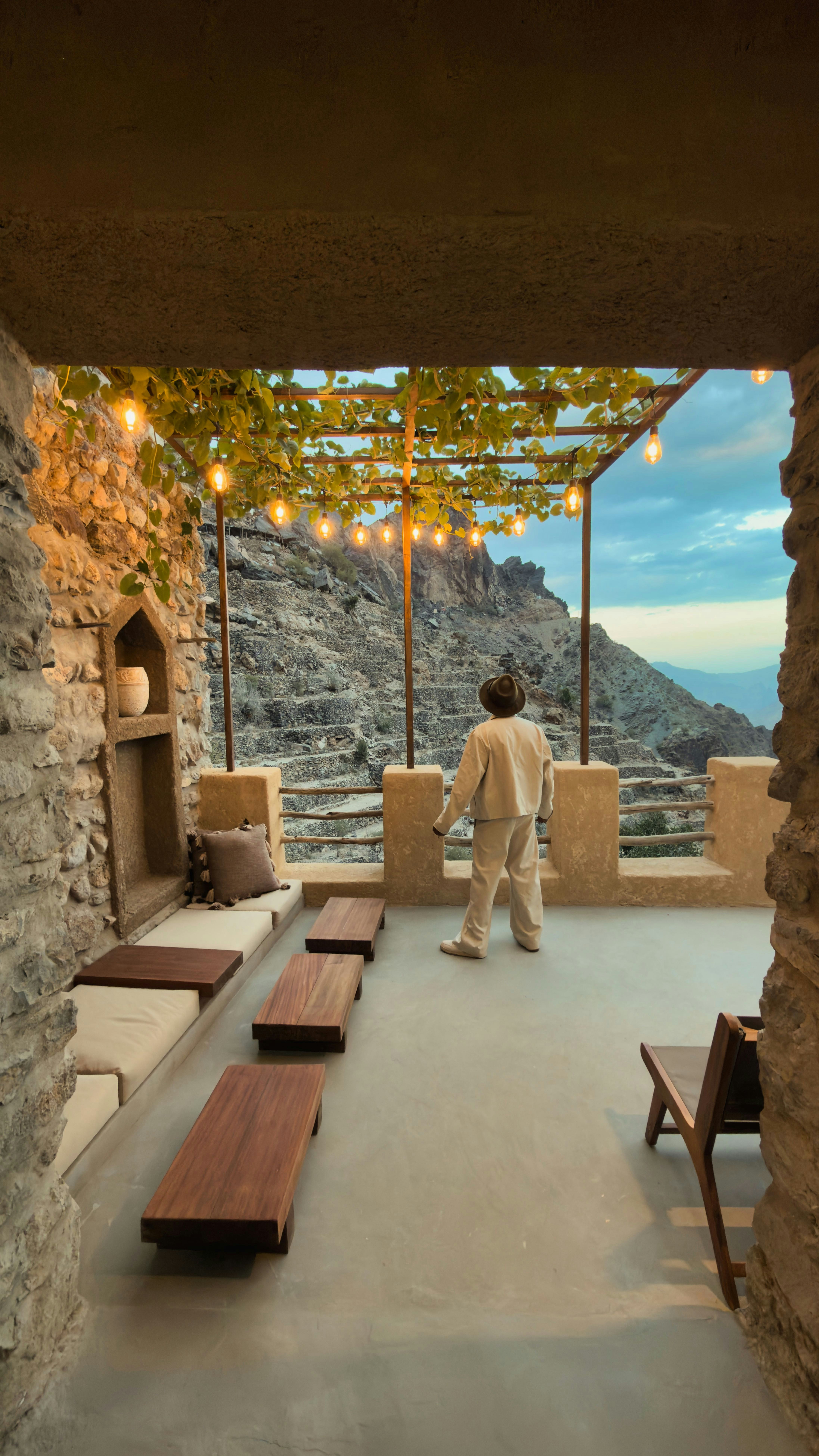 Terrace at Sunset: A Lone Traveler Beneath Vine-Wrapped Beams