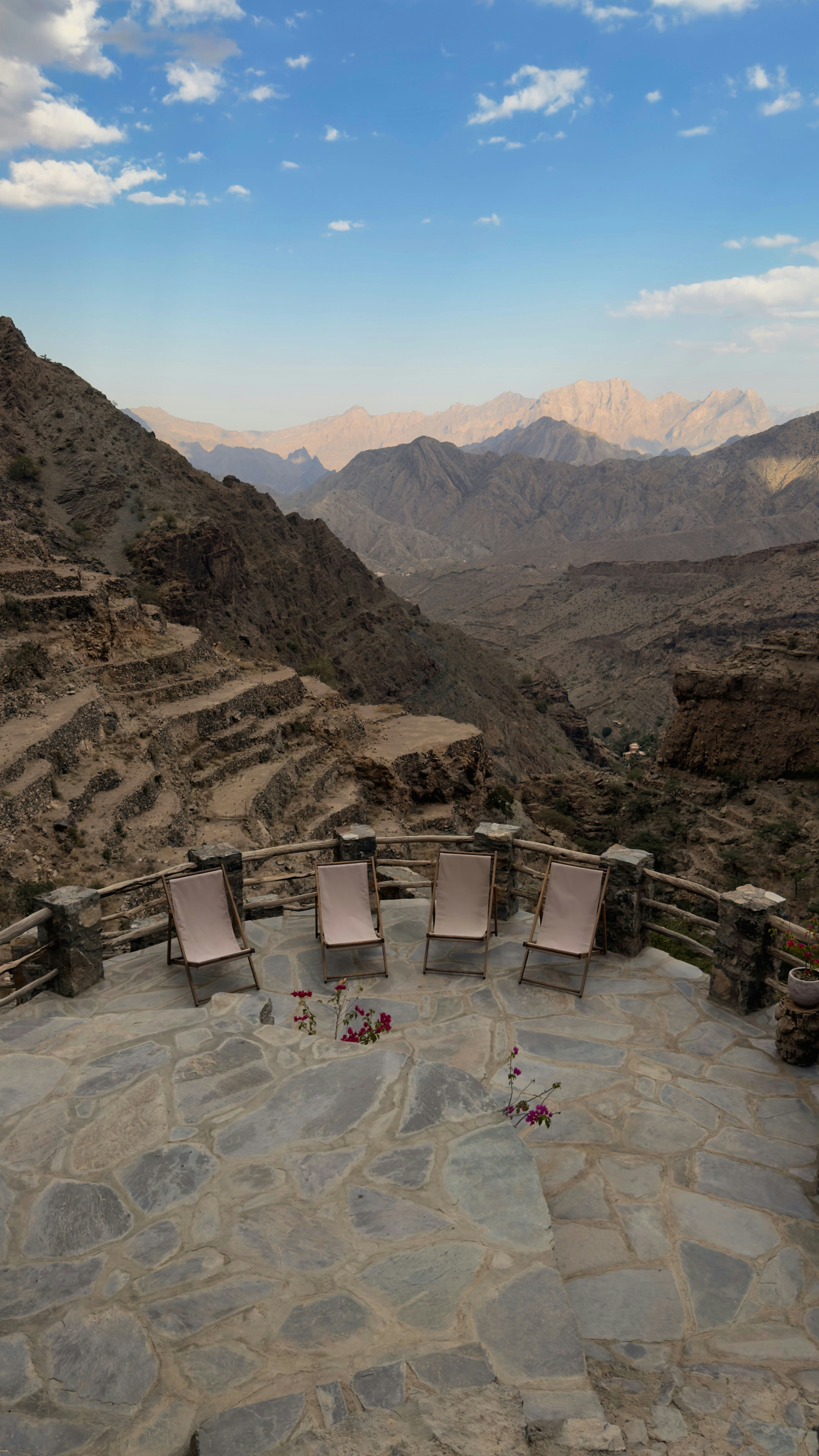 Four lounge chairs on a stone patio overlooking mountains