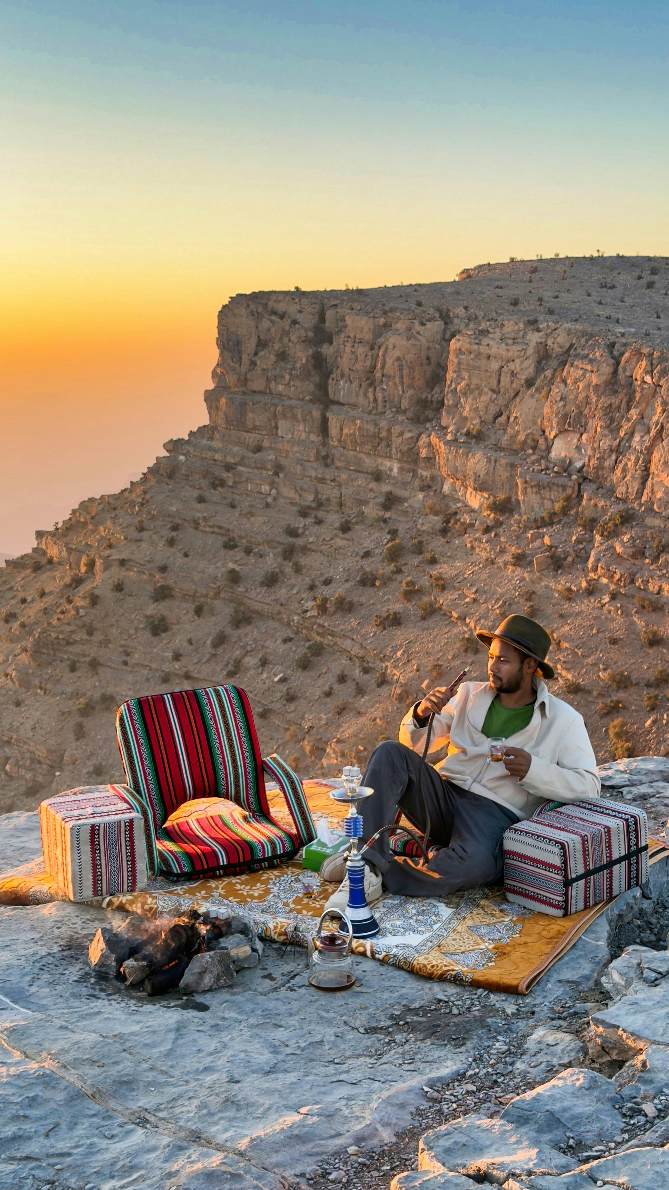 Man smoking hookah on mountain at sunset