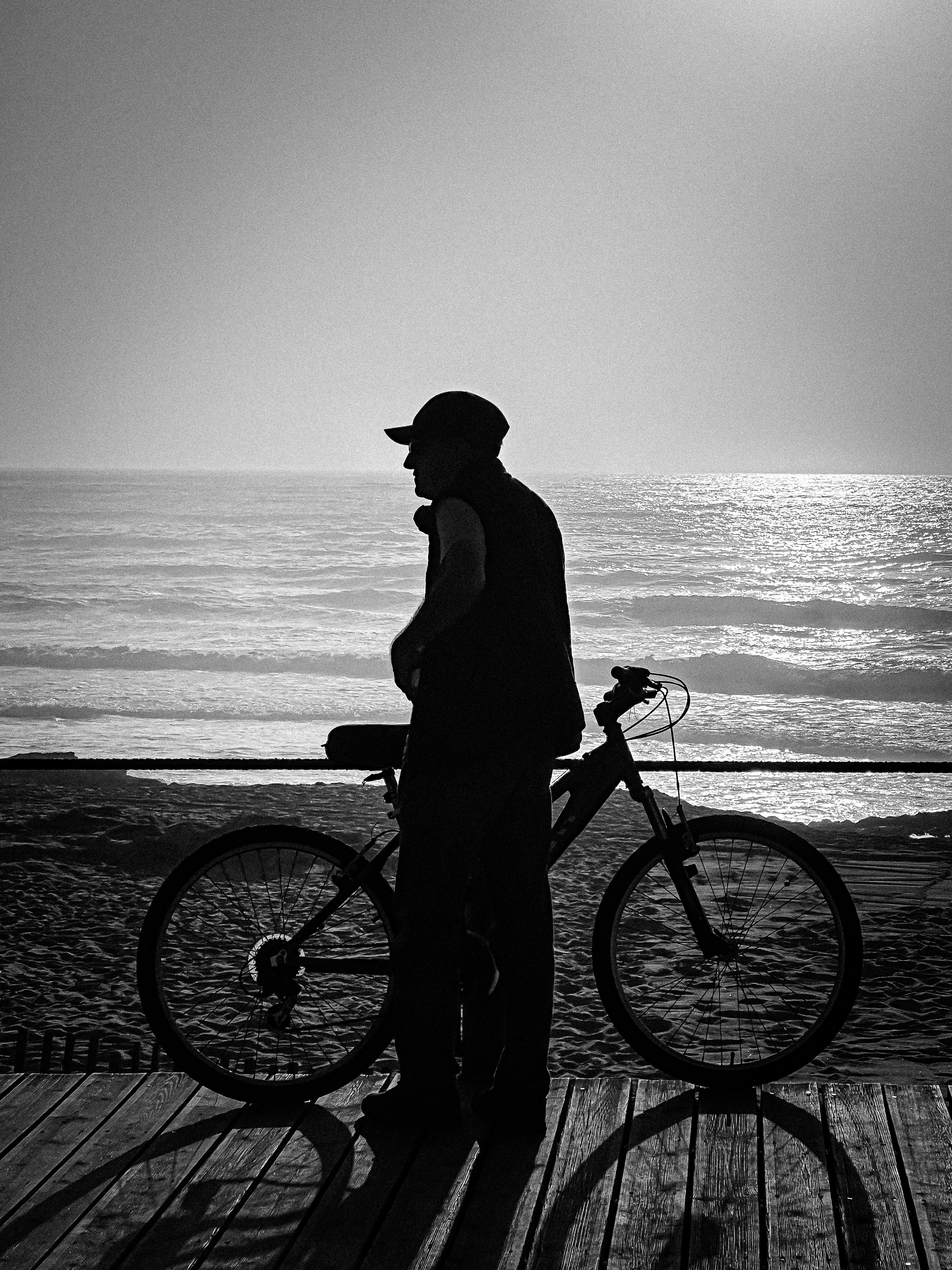 Silhouette at the Seawall: A Rider Pauses by the Shore