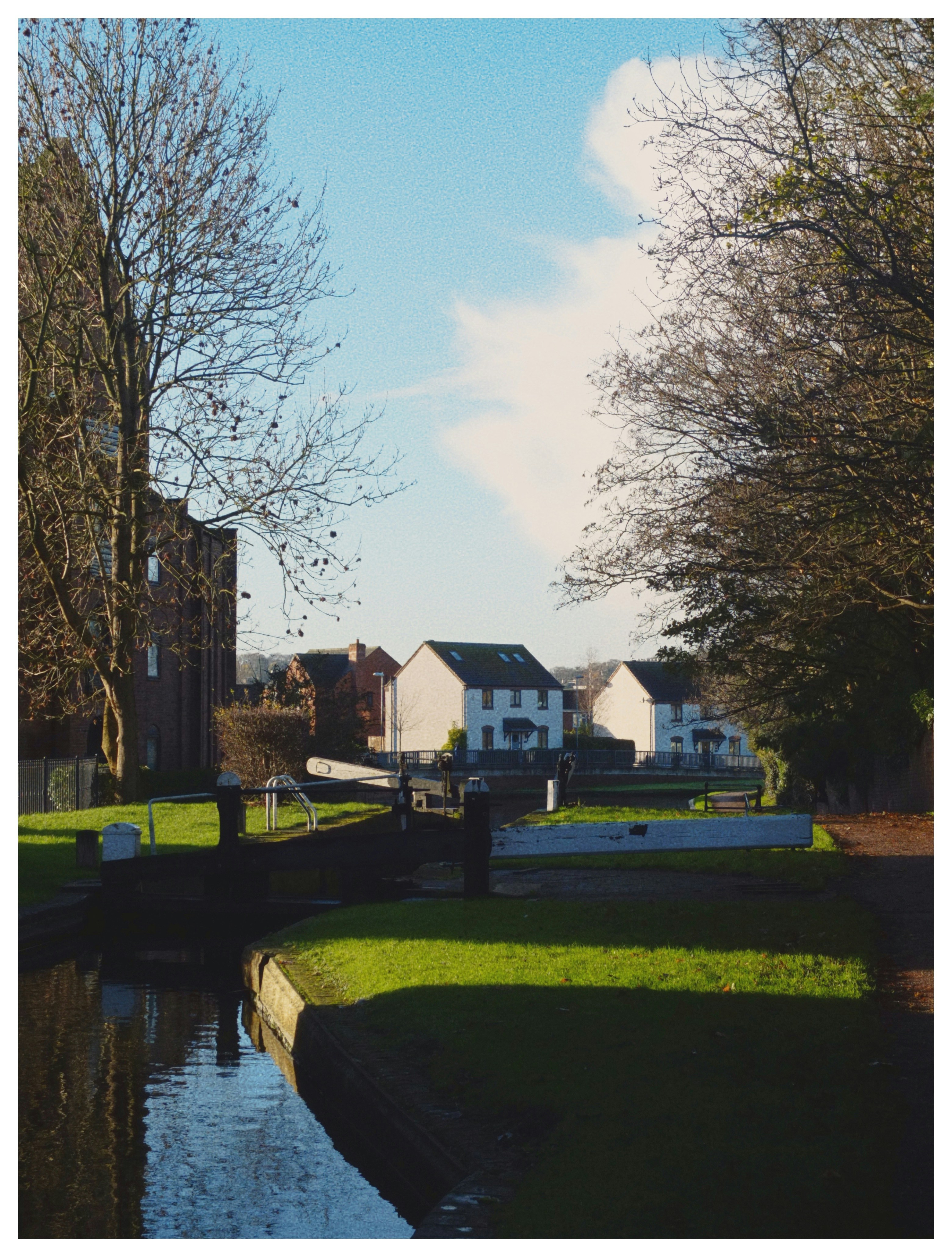 Quiet canal drama: early sun, bridge silhouette, and white houses