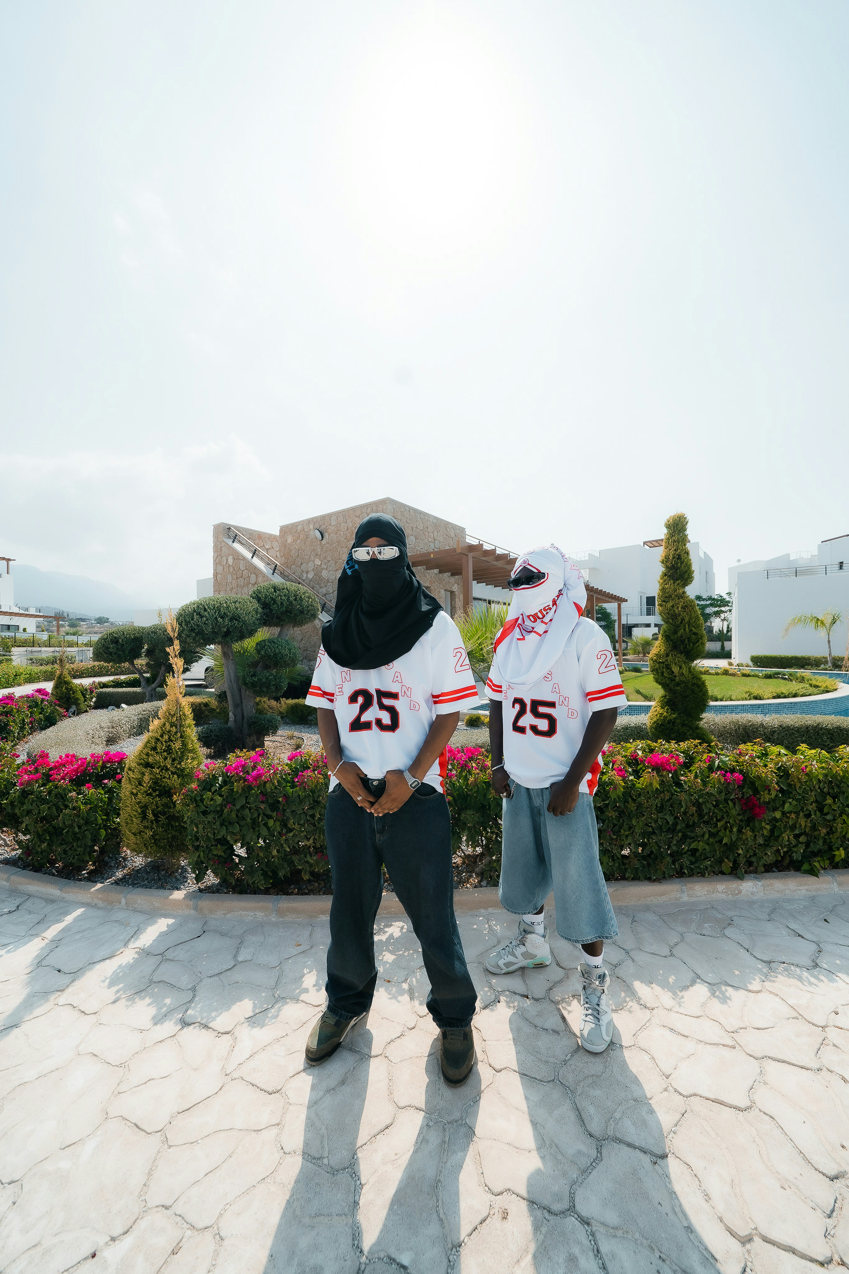 Two Young Men in Matching Jerseys Stand Under Bright Sky