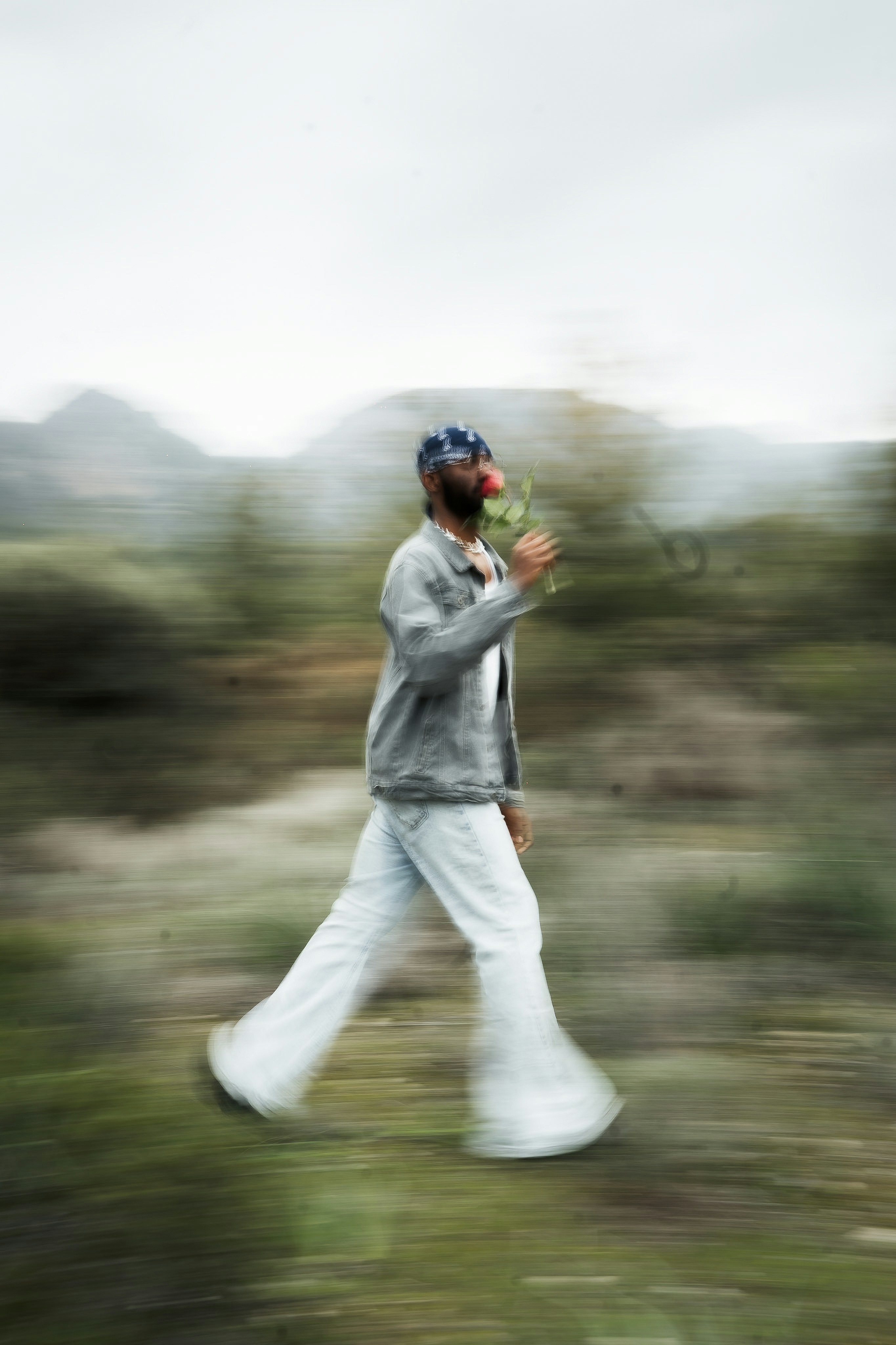 Motion and emotion captured in one frame — a walking portrait with artistic blur, featuring a man holding a rose in a serene outdoor landscape.