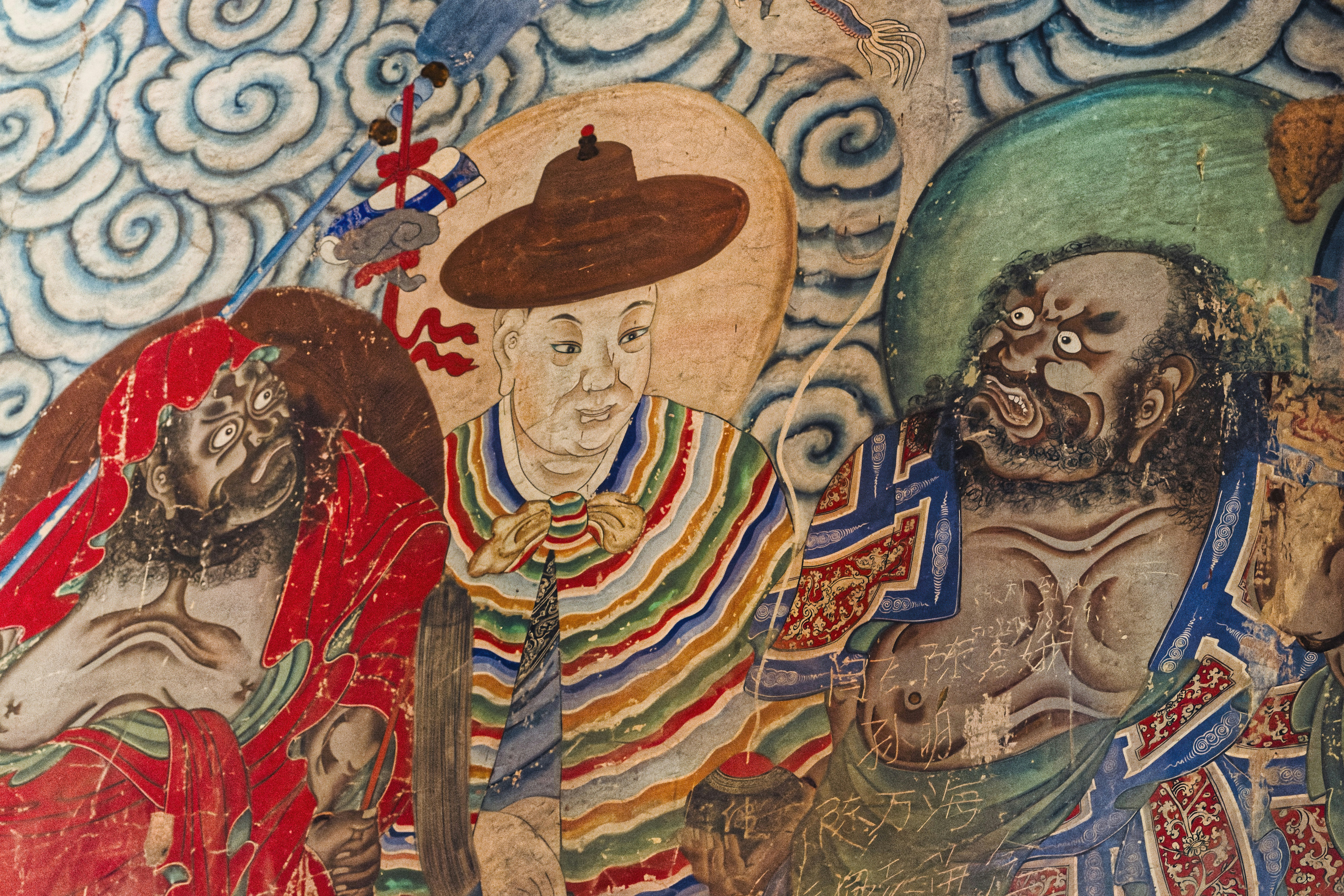 Three Figures in a Sacred Scene: A Hooded Monk Between Mythic Beings