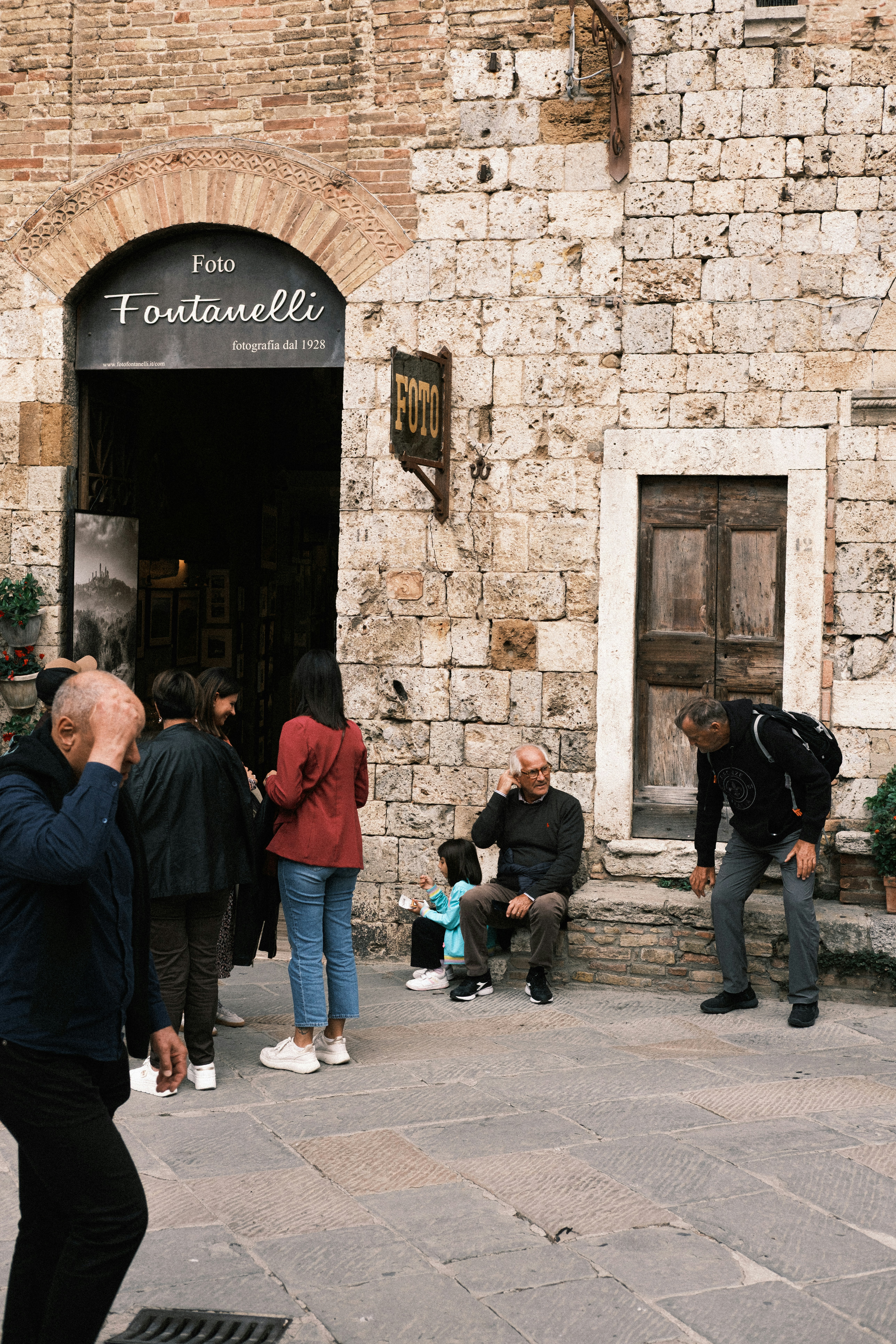 Street doorway at Foto Fontanelli: locals gather near a historic stone facade