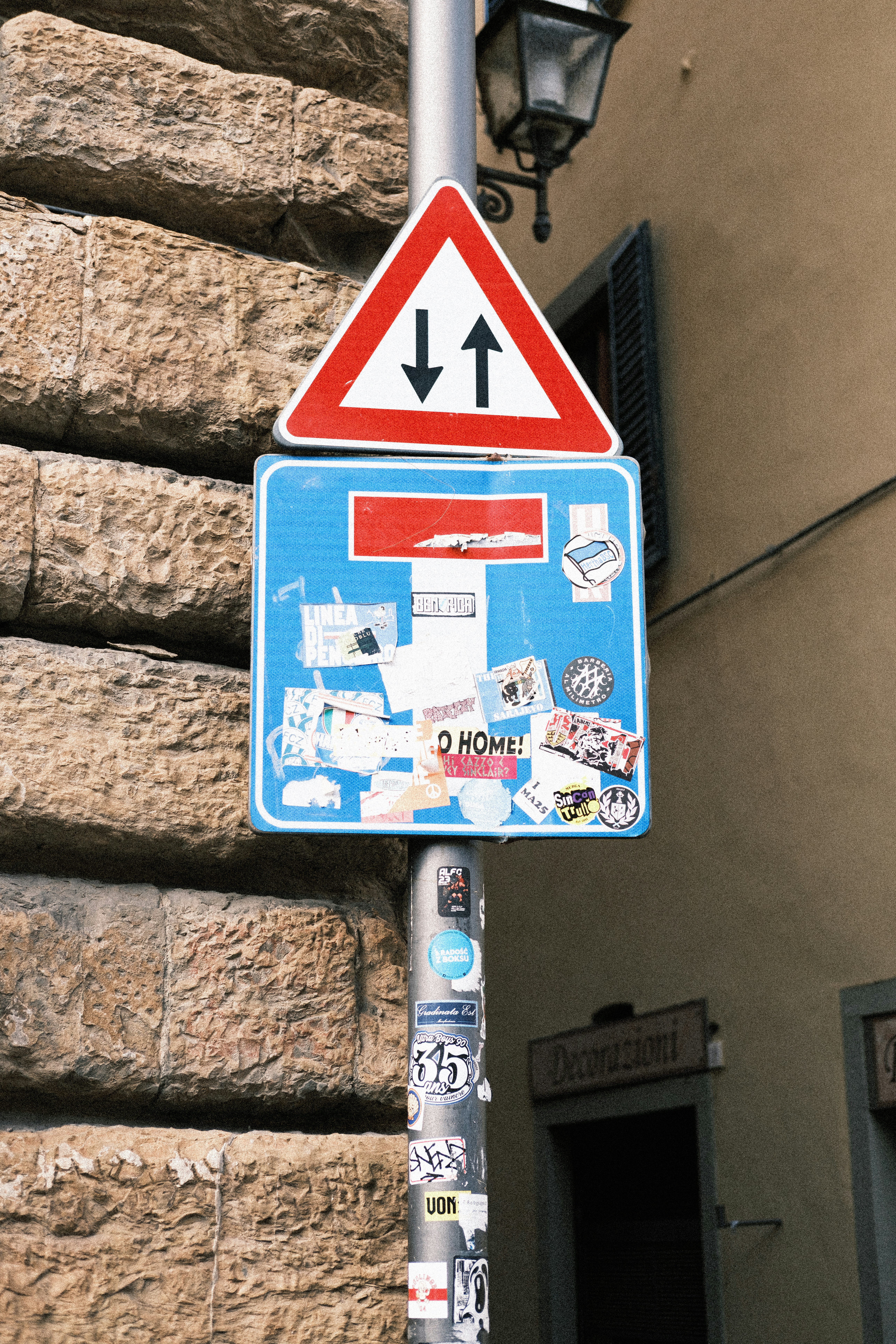 Stickered Blue Sign Amid Rough Stone Facade