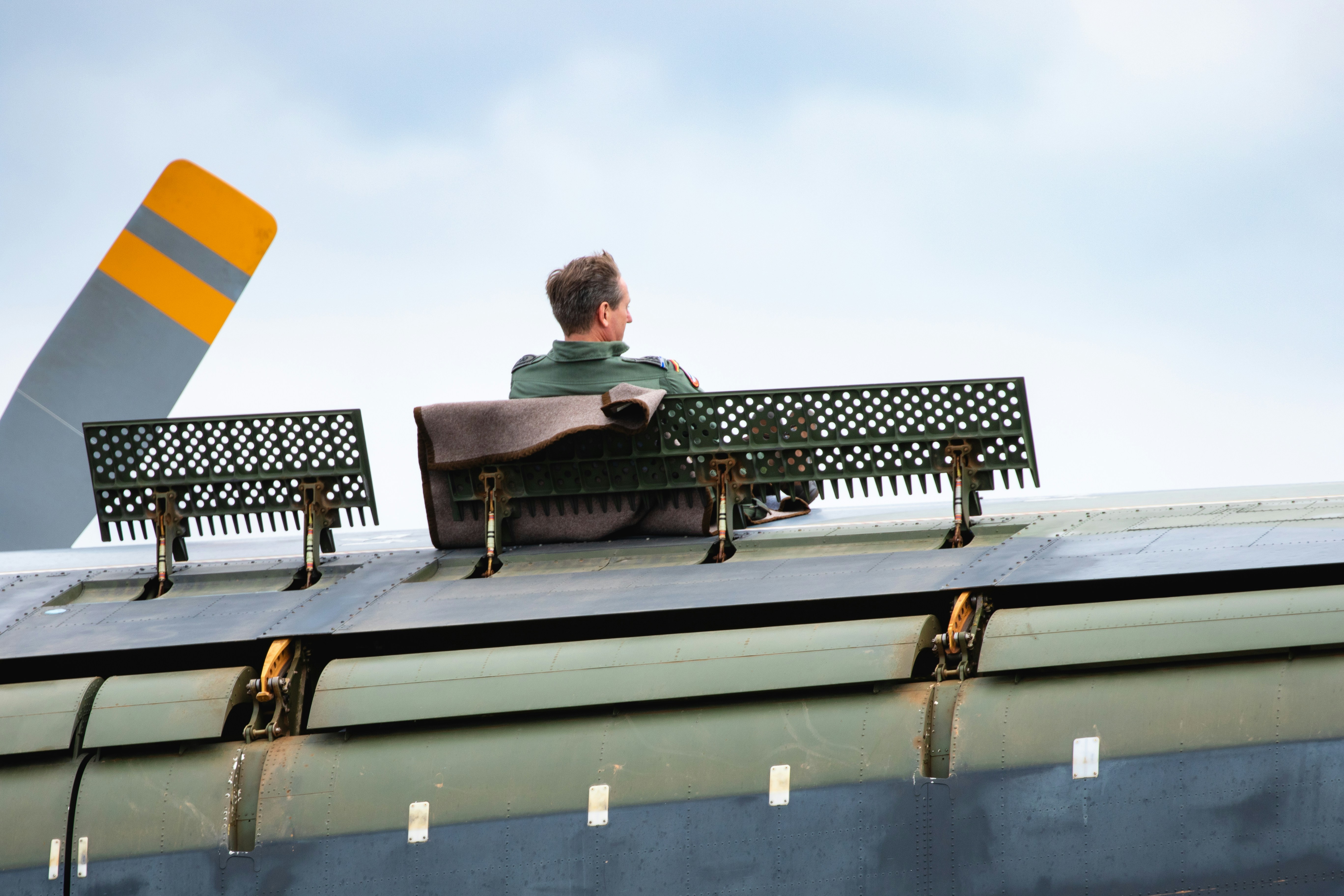 Rooftop Respite: A Man Seated on a Weathered Bench Above the Tarmac