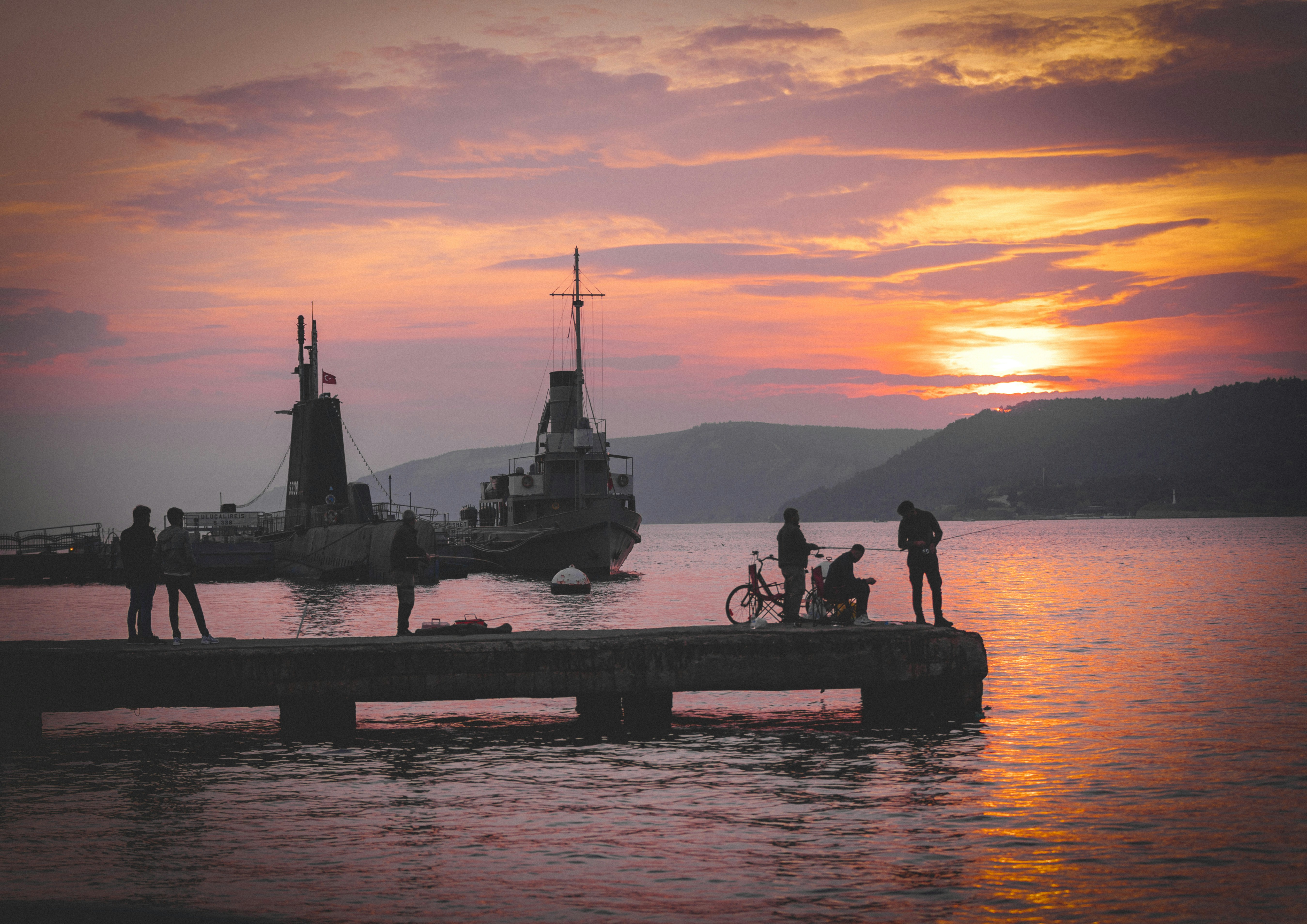 Dusk on the Pier: Figures and Tugboats at Sunset Harbor