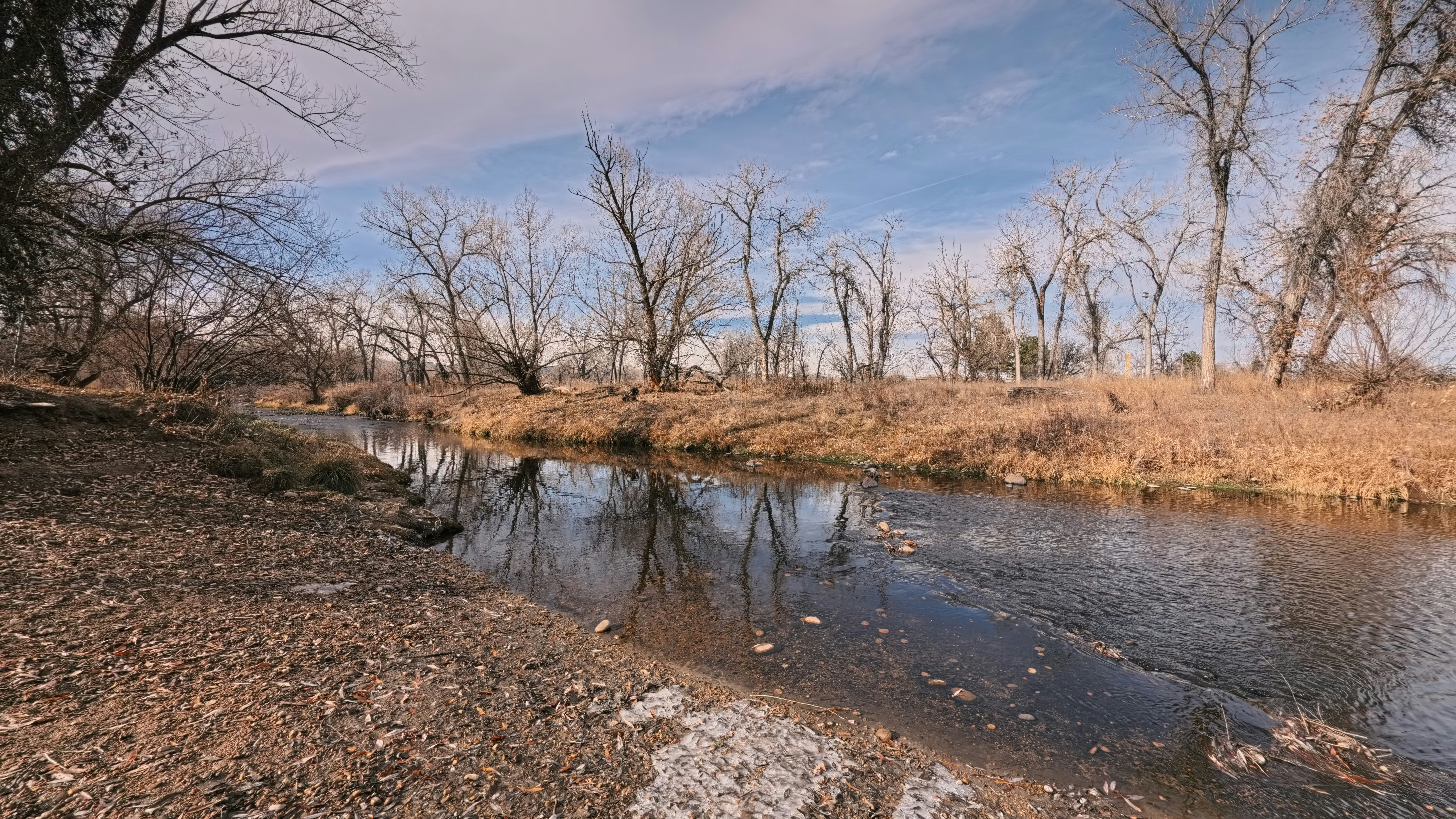A calm river flows through a bare winter landscape.