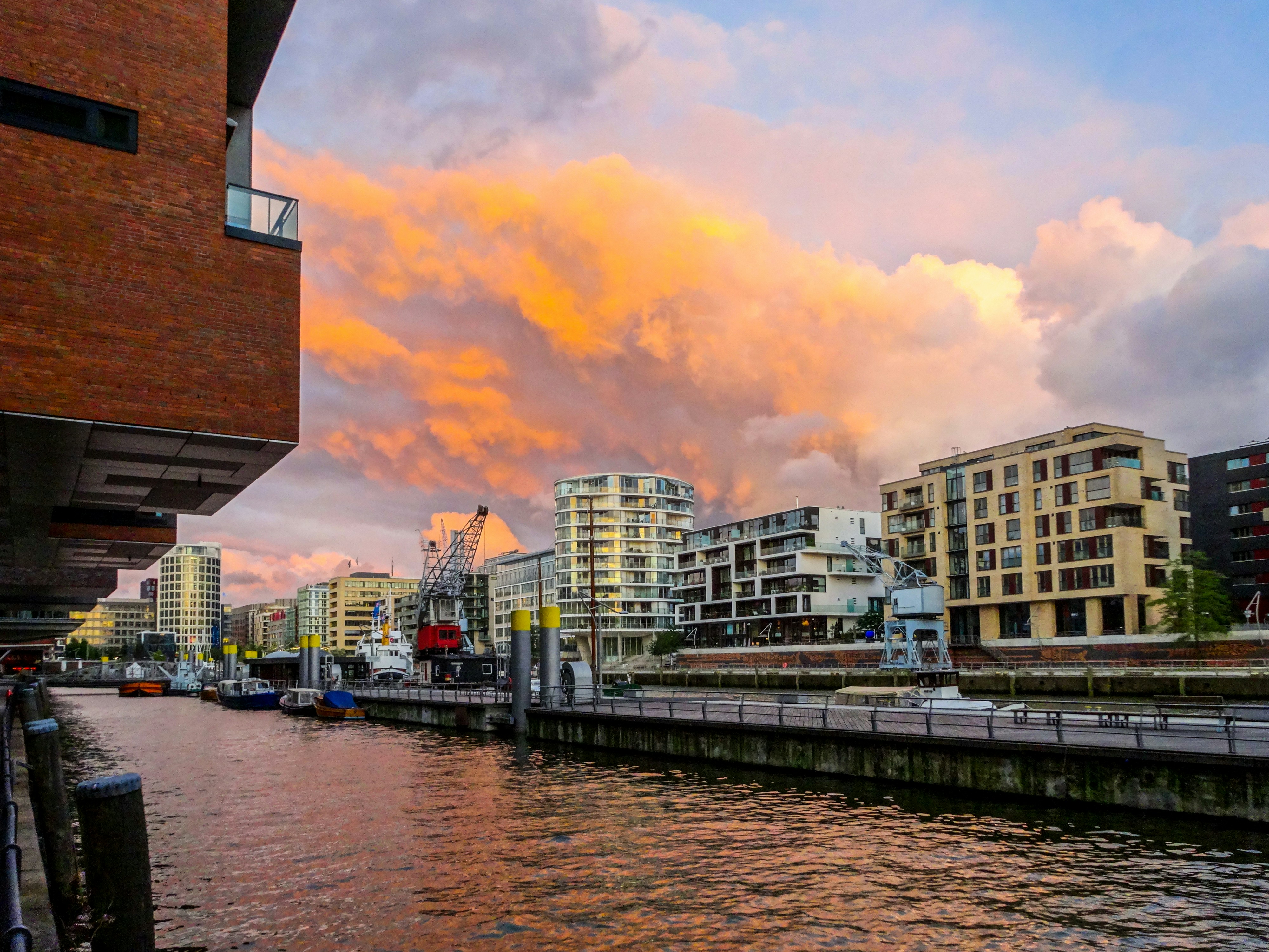 Urban canal at sunset: warm clouds above modern docks