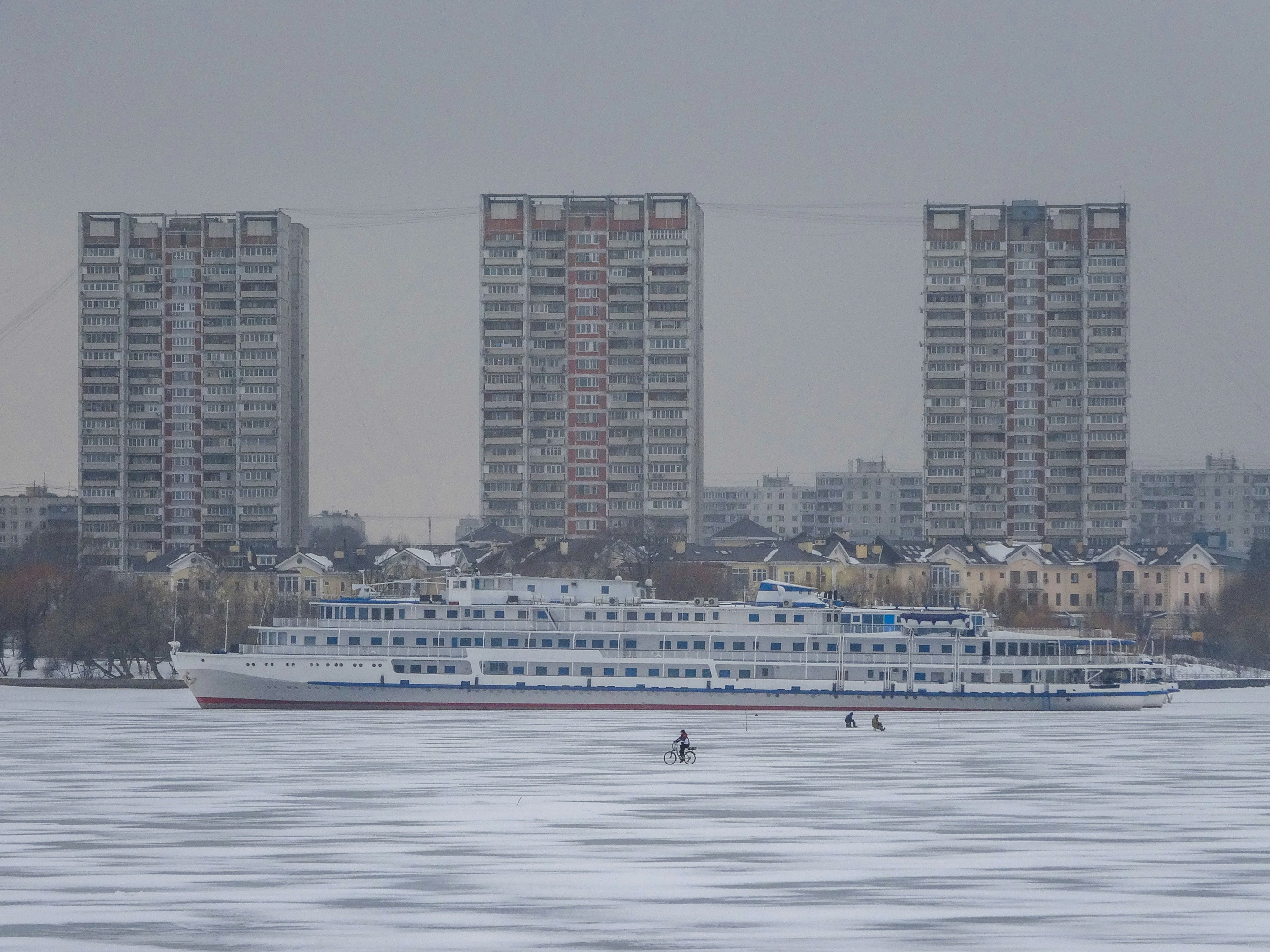 Riverine Parade: A Passenger Vessel Cleaves a Calm Waterway with Urban Backdrop