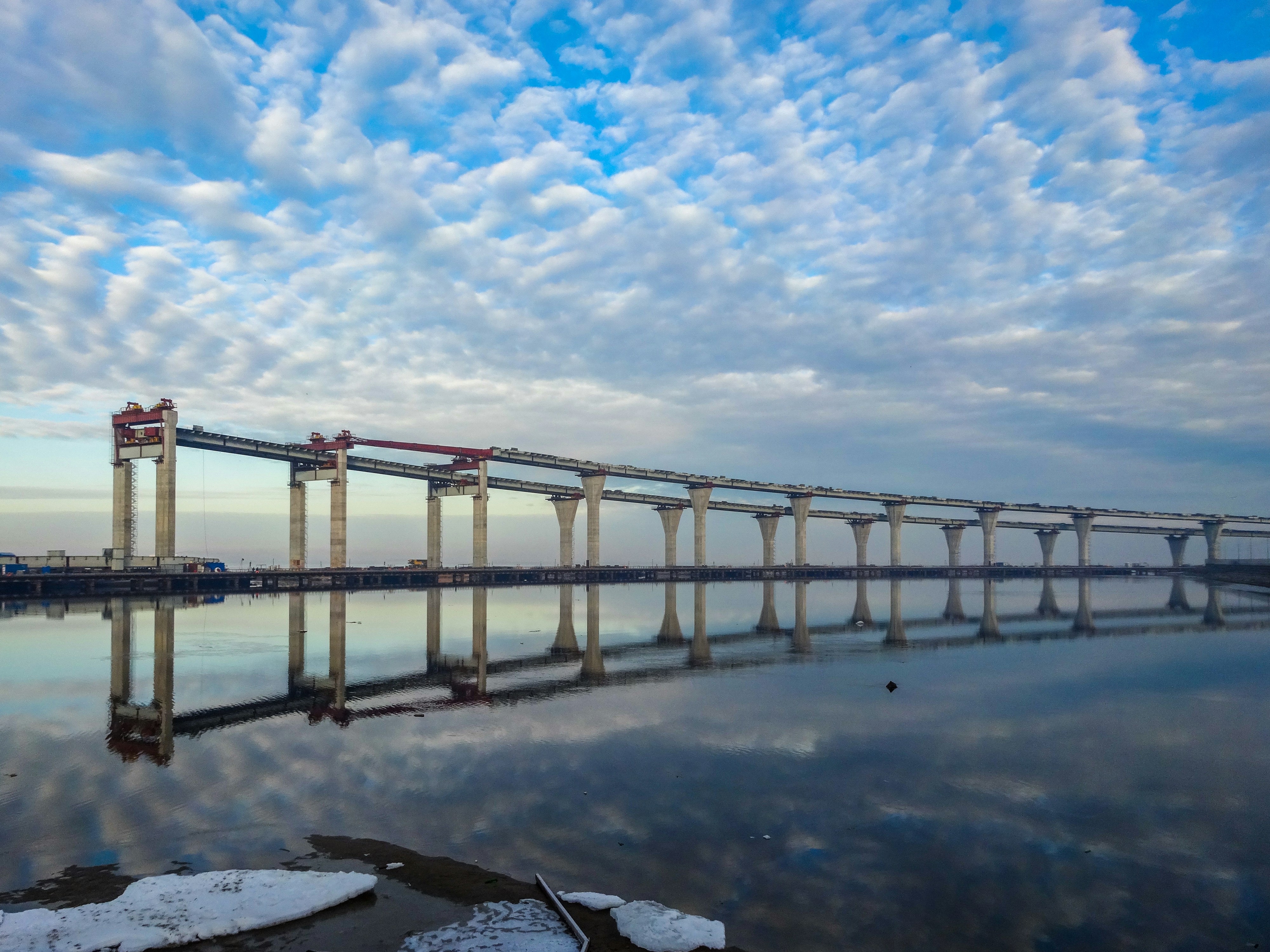Bridge construction over calm water with reflections