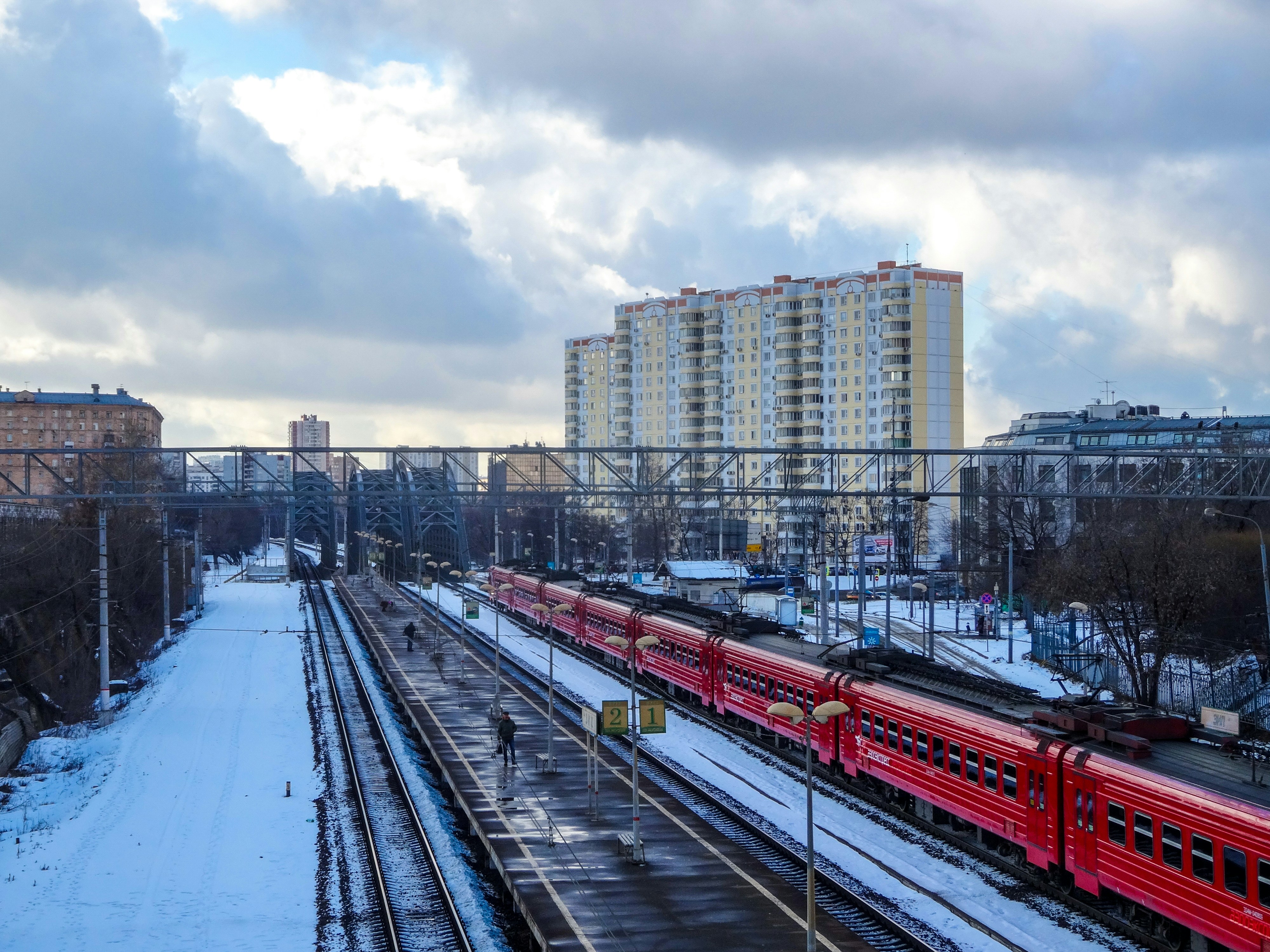 Red train on tracks with snowy buildings in background