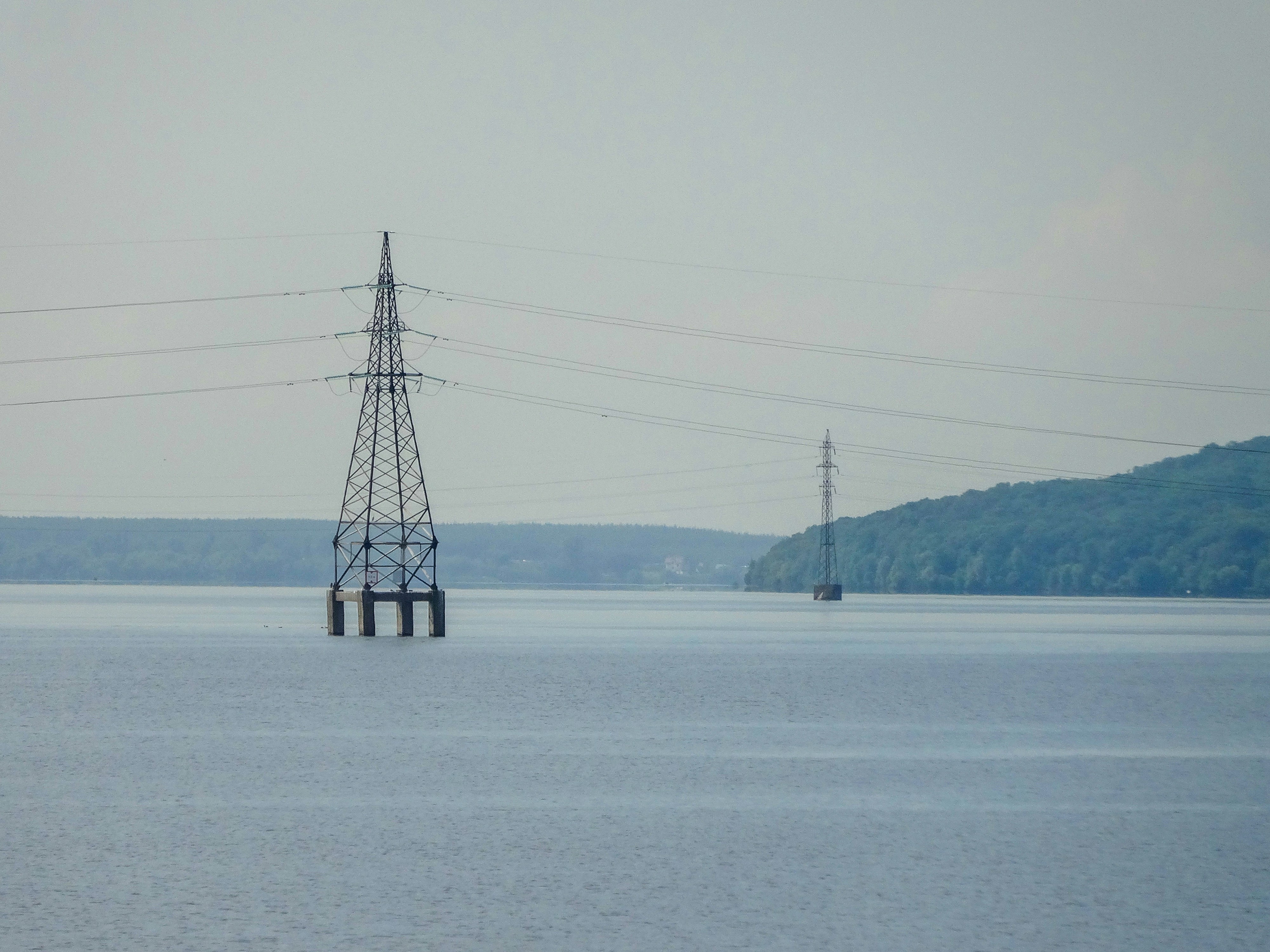 Power towers stand in a calm body of water.