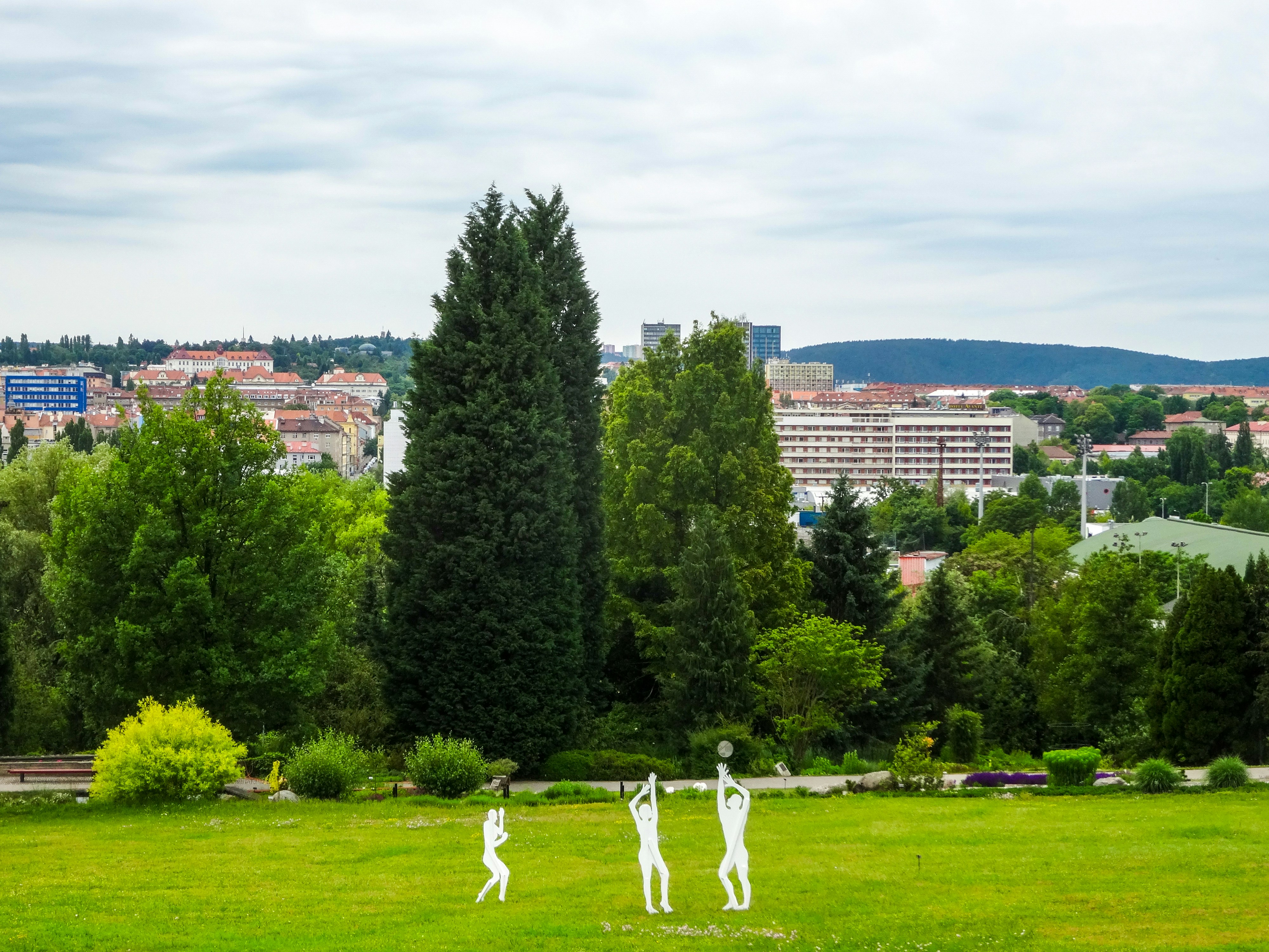 Three silhouetted dancers in a sunlit city park
