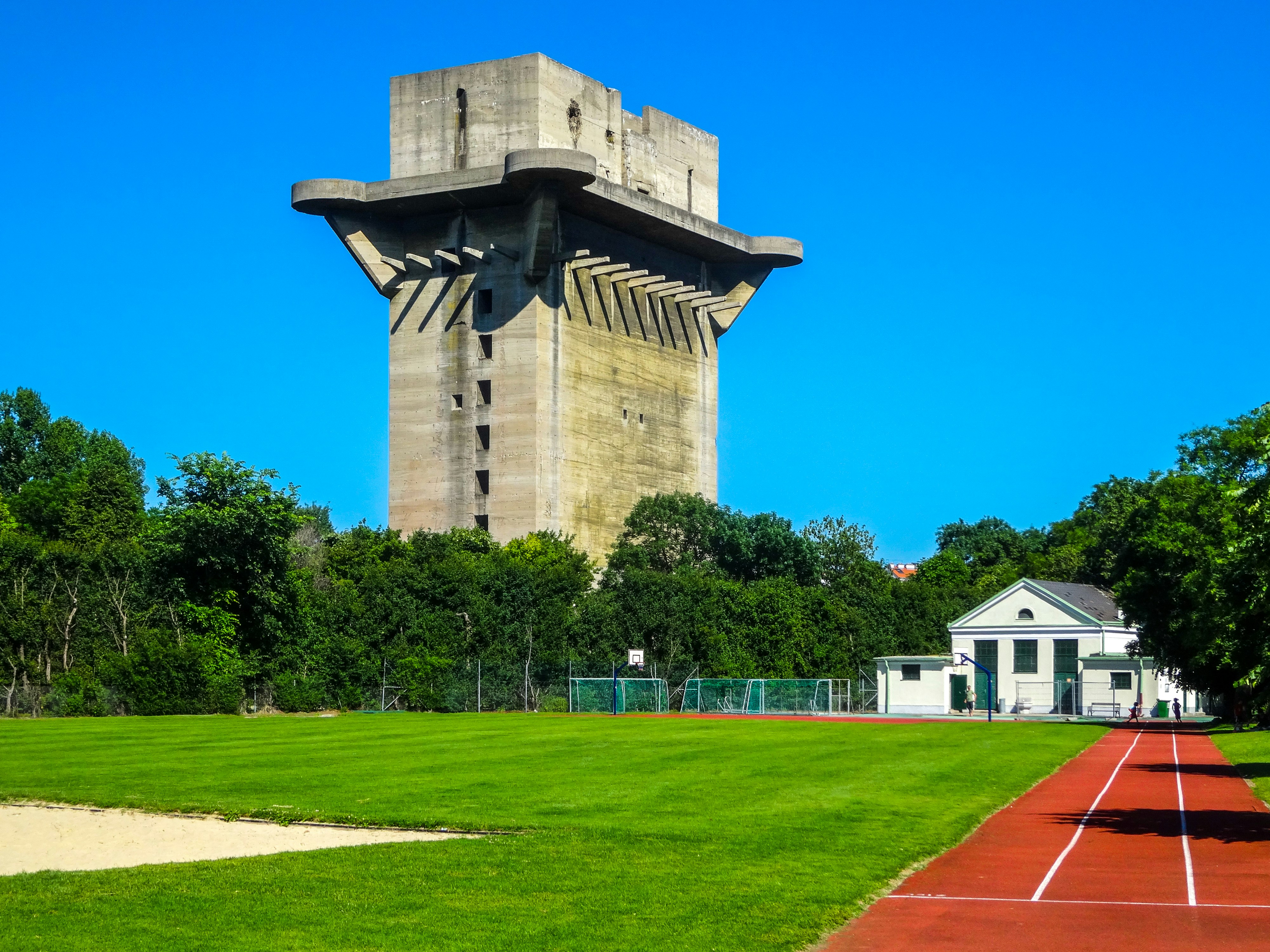 Tall concrete tower next to green field and track