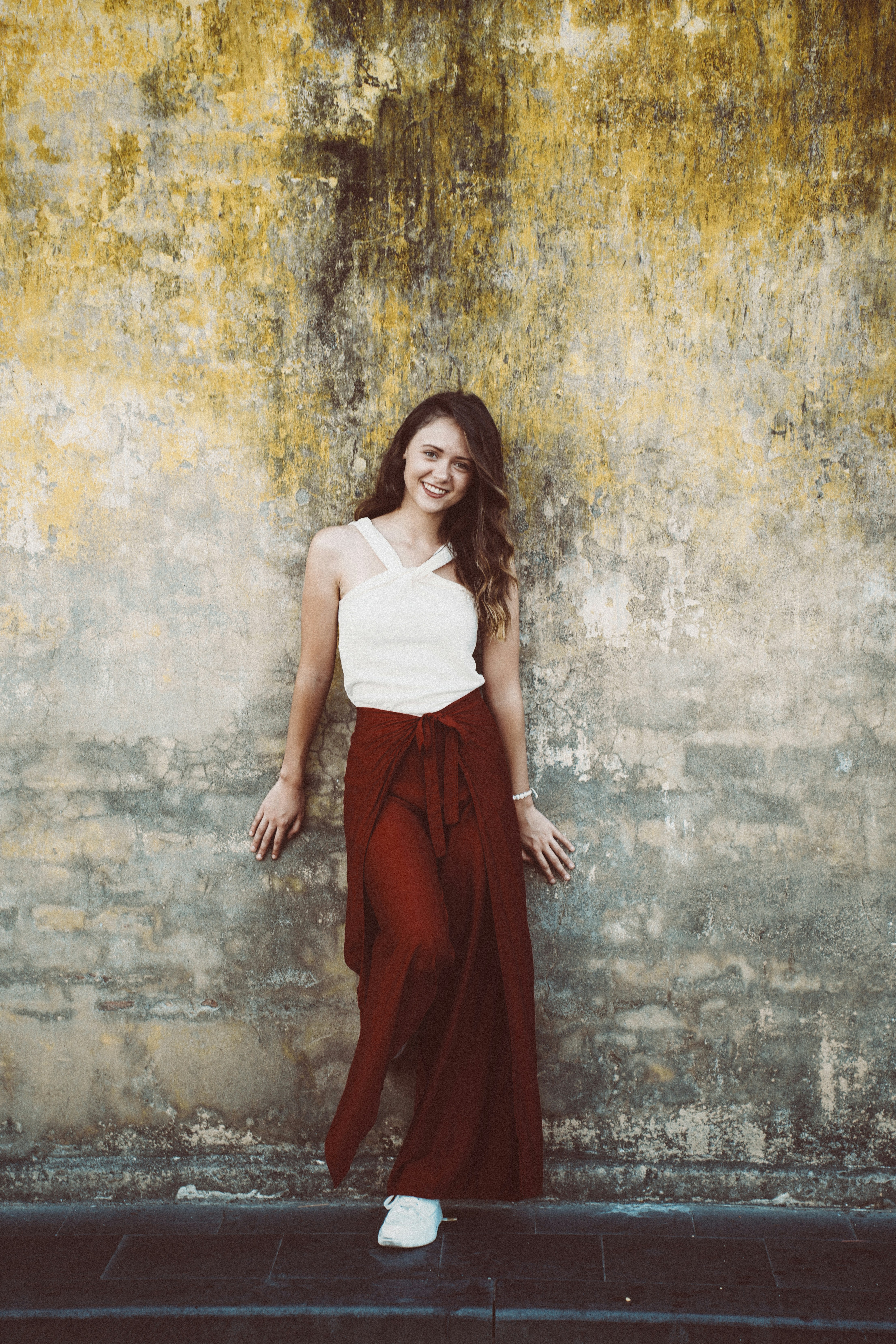 Against a Weathered Wall: A Confident Portrait in Ivory and Crimson