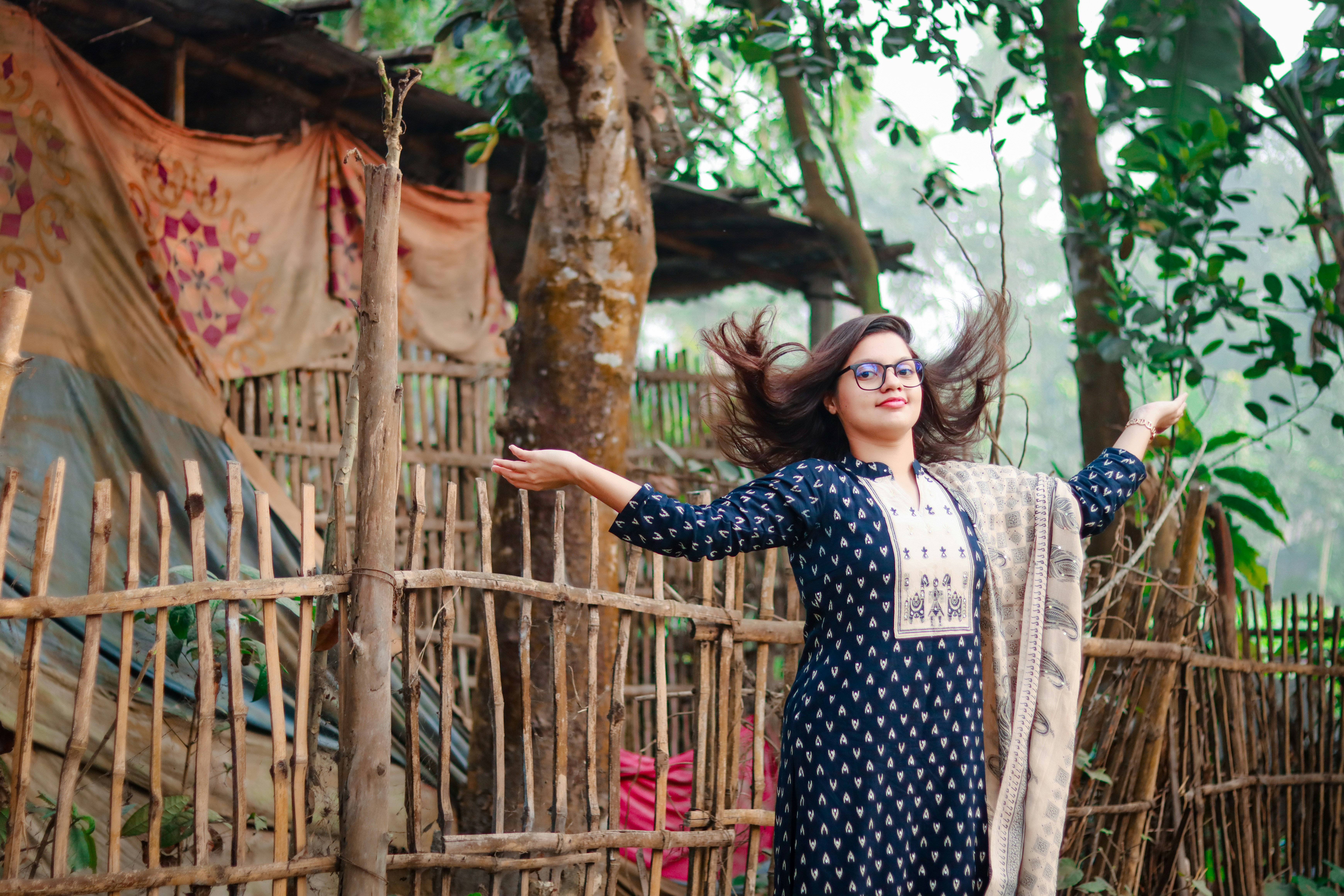 Blue-dotted dress in a sunlit village yard with swinging scarf
