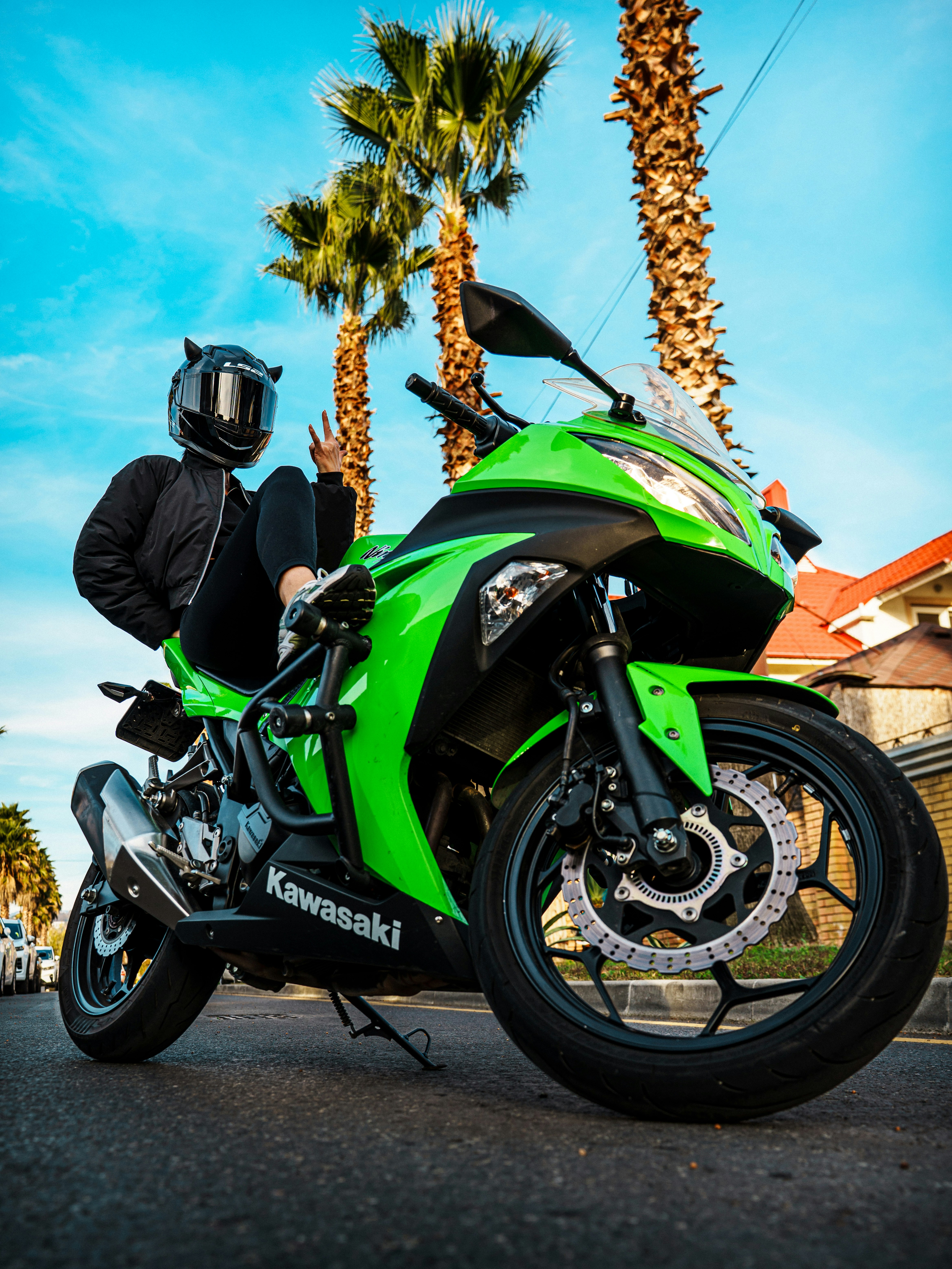 Green Thunder: A Rider Straddles a Slick Kawasaki Under Palm Trees
