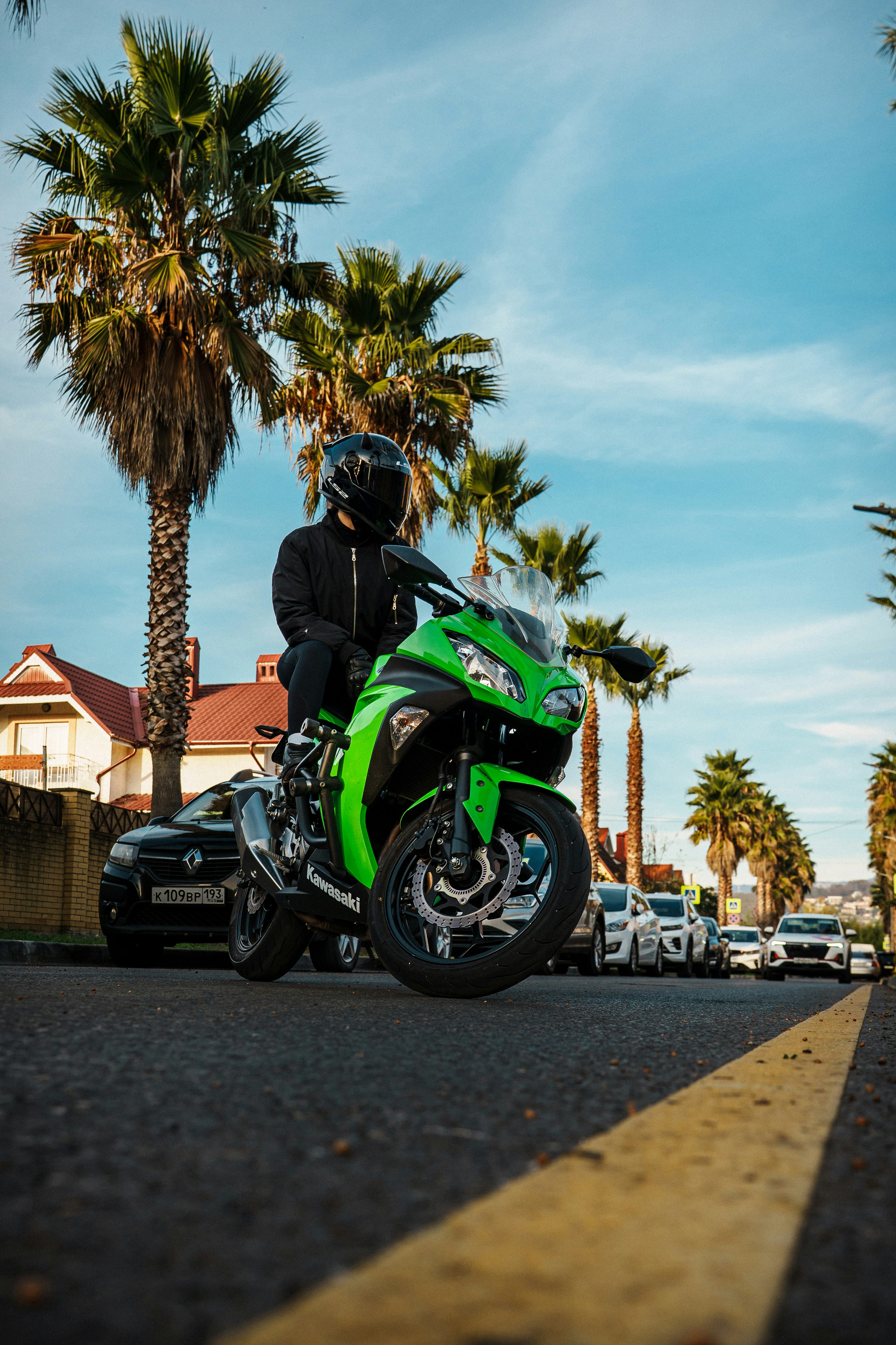 Green motorcycle power stance under palm-lined street