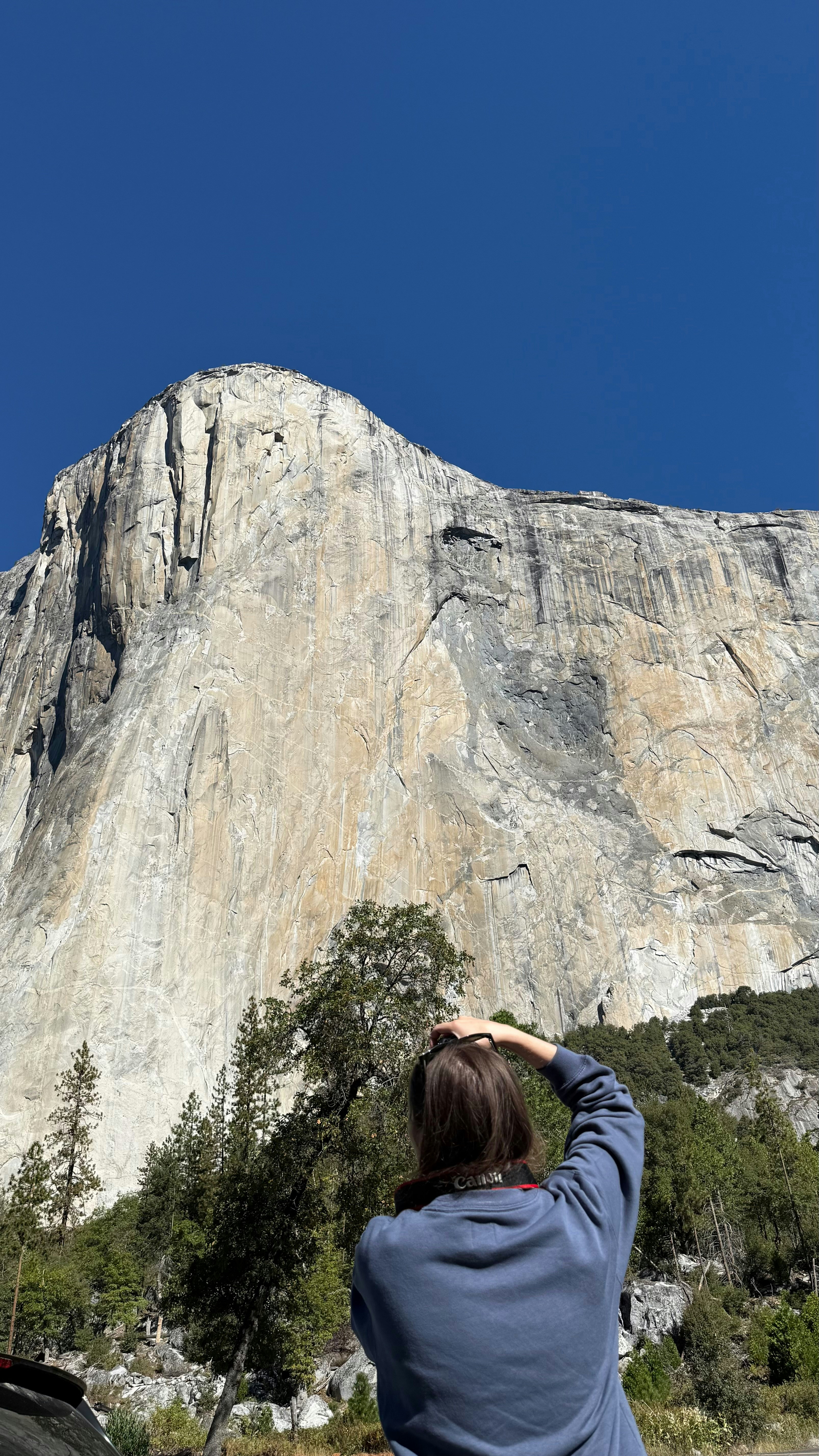 Climber Beneath a Monolithic Wall: A Back View at Distant Peak