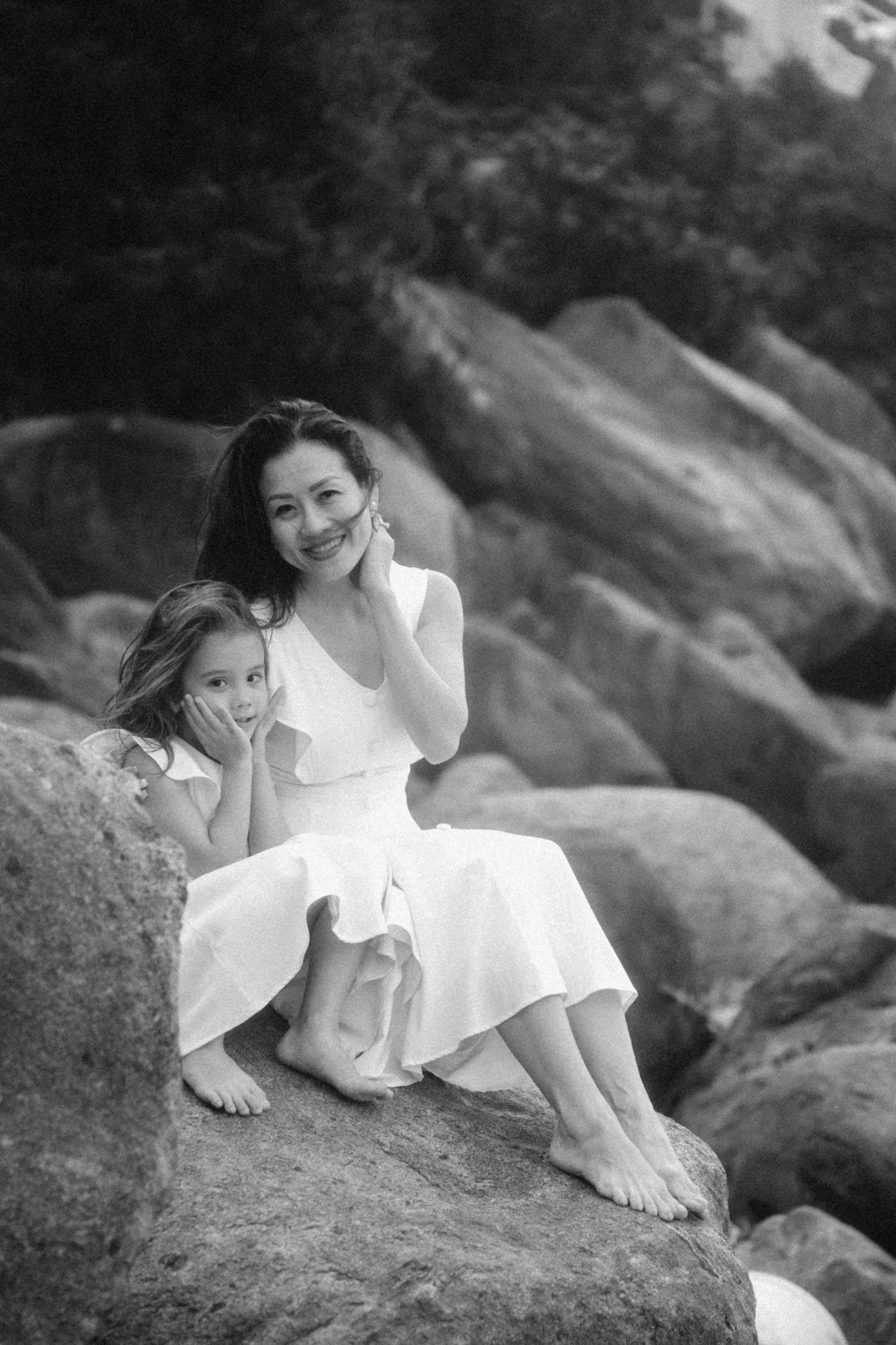 Mother and daughter in quiet contemplation atop a sunlit rock