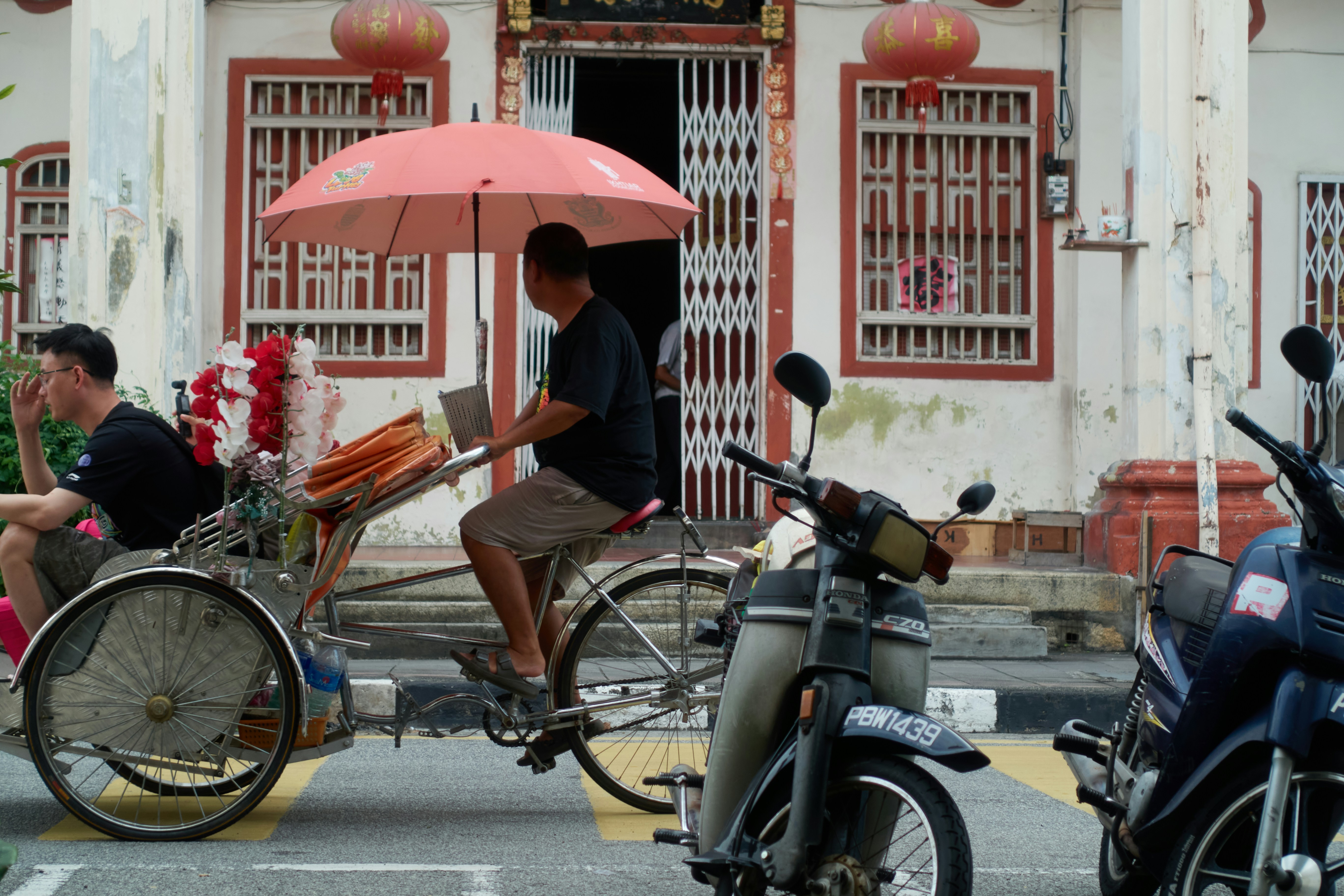 Umbrella Rider: A Street Scene with Red Lanterns and Bicycle Commerce