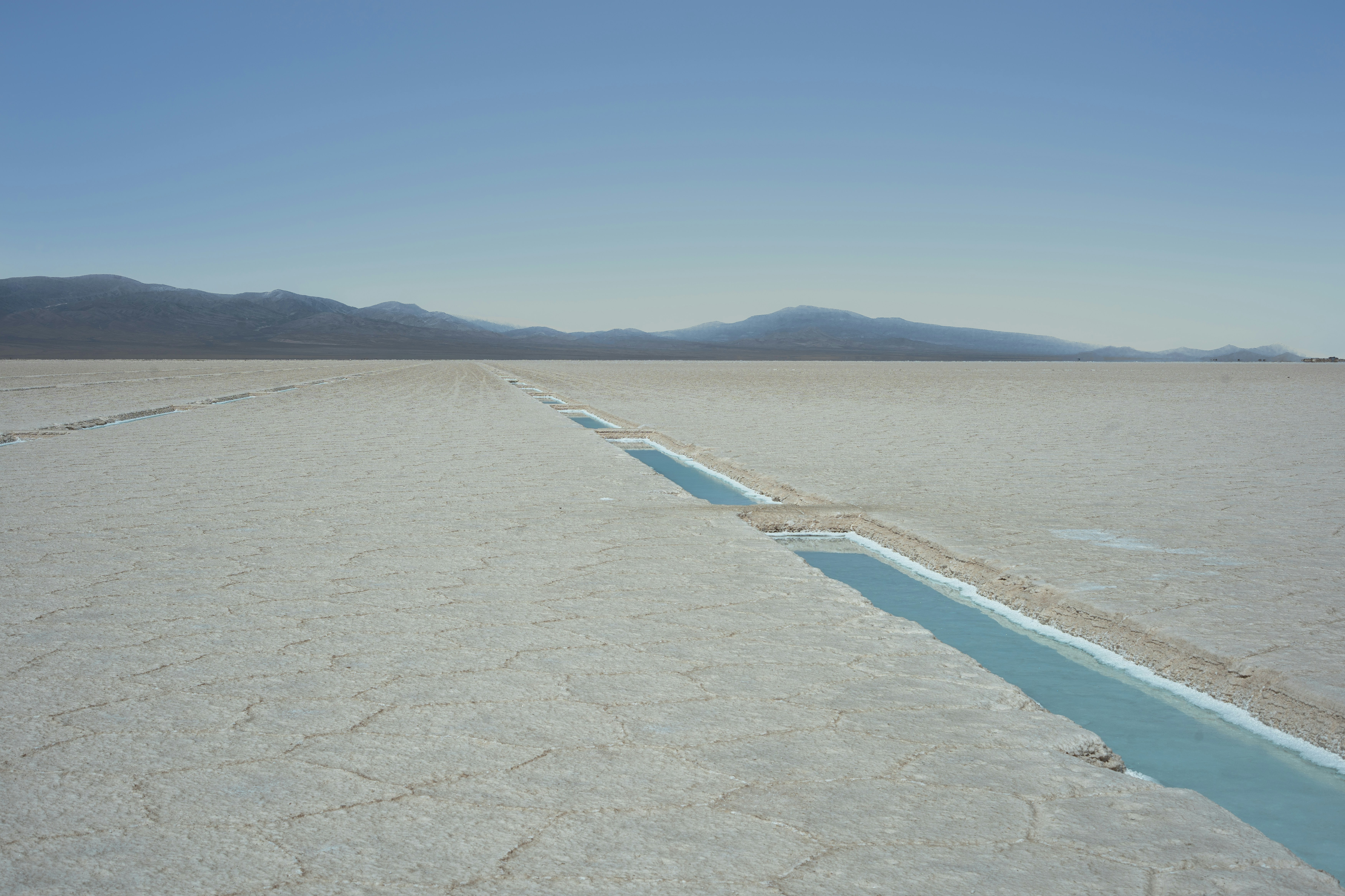 Shallow salt lake reflecting the mountains and sky, creating a perfect mirror surface.