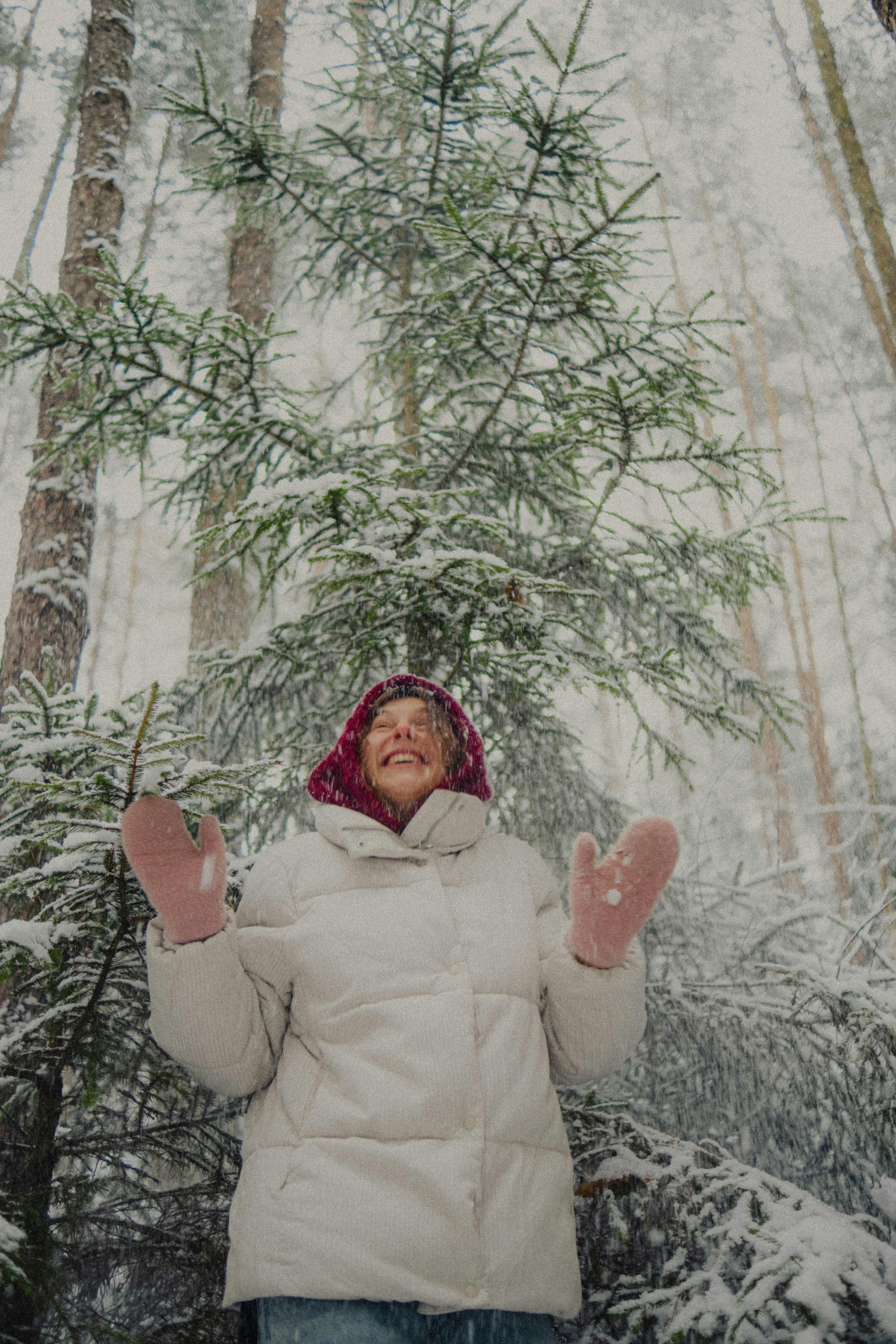 Joyful Snowfall: Woman Reaches Skyward Among Frosted Trees