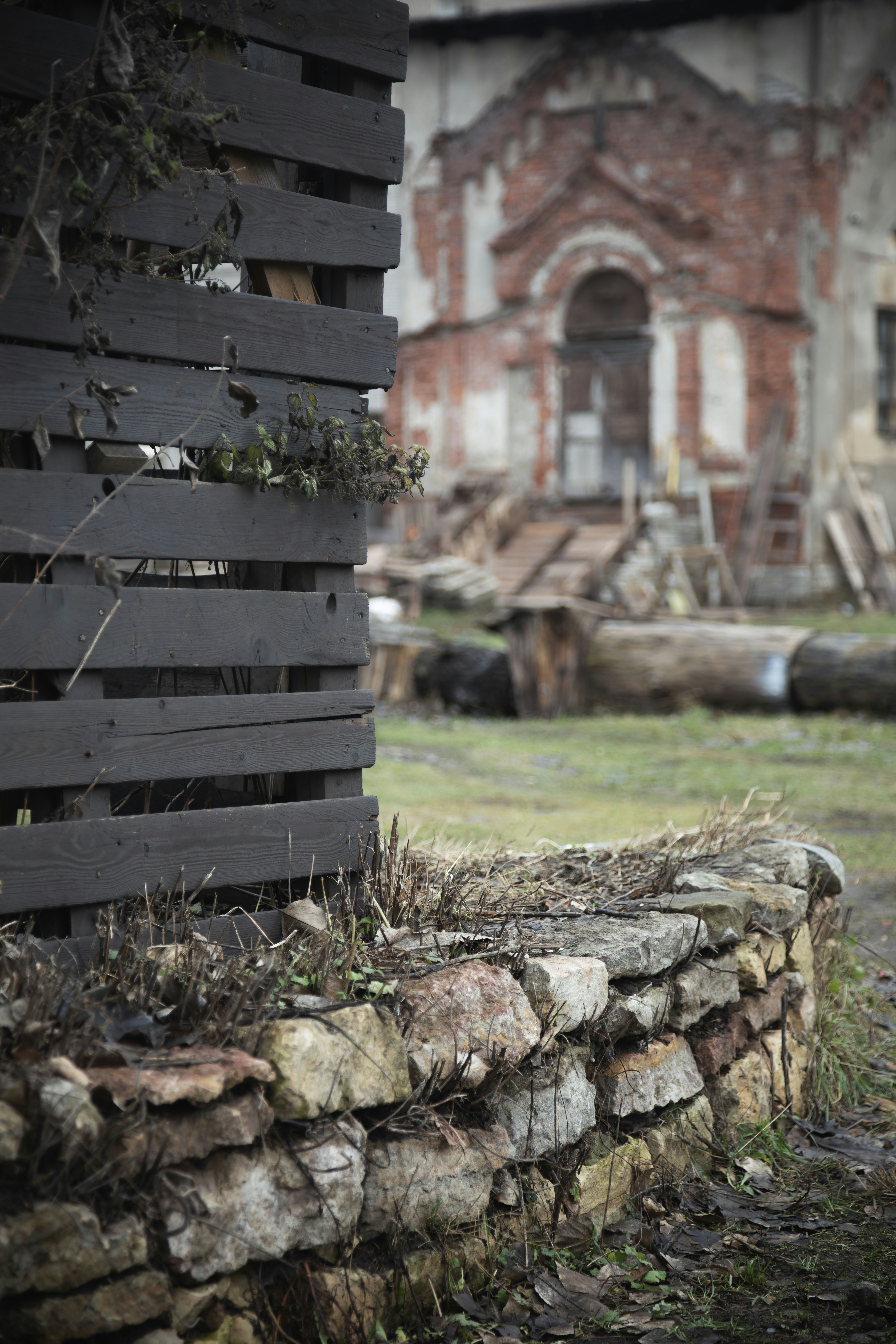 Ruined Archway Beyond a Weathered Fence and Stone Wall