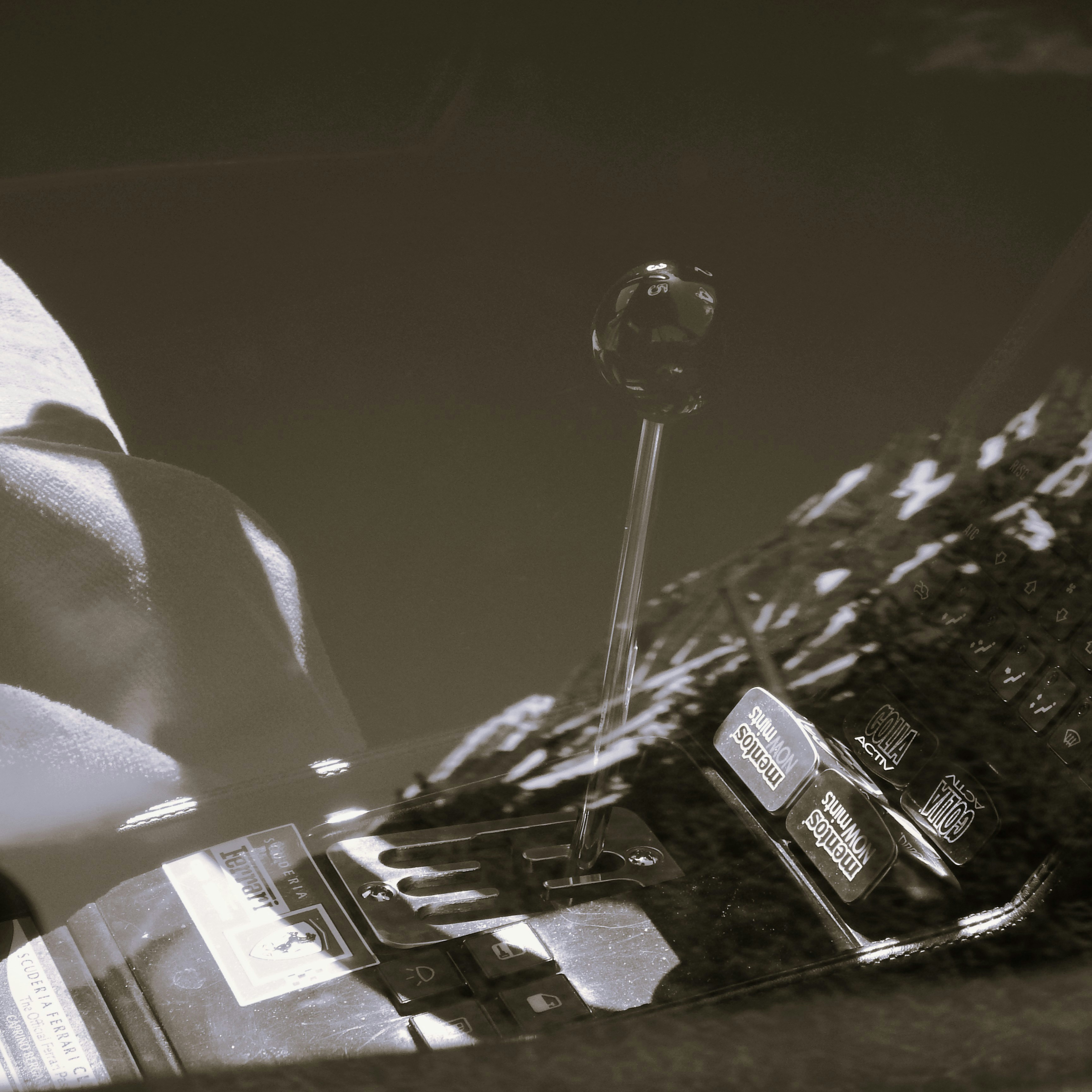 Manual gear lever of a Ferrari, picture taken in mountain. Picture of the interior of the Ferrari. Background mountain.