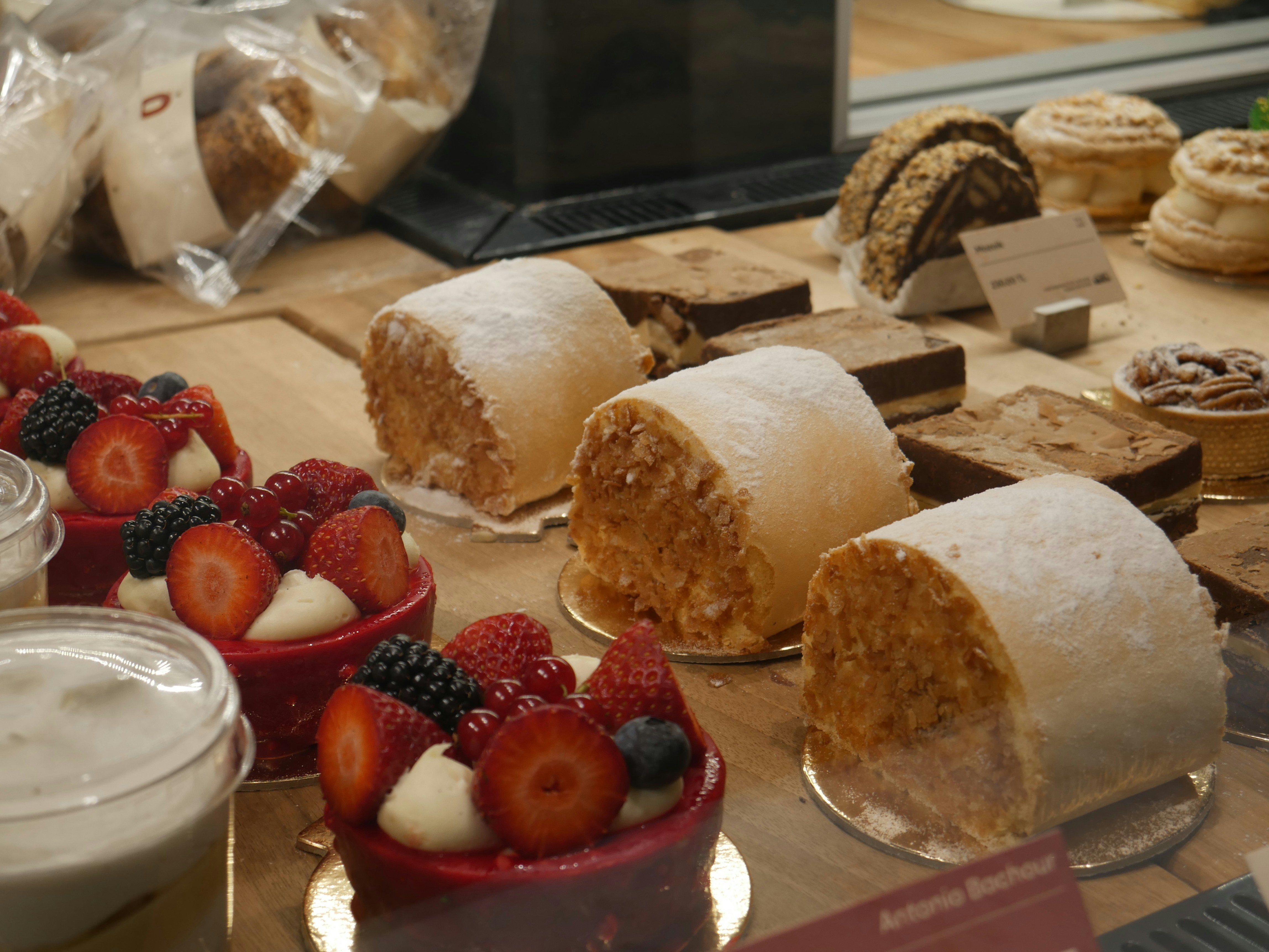Curved Creme Puffs and Berry Tarts at a Gleaming Pastry Display