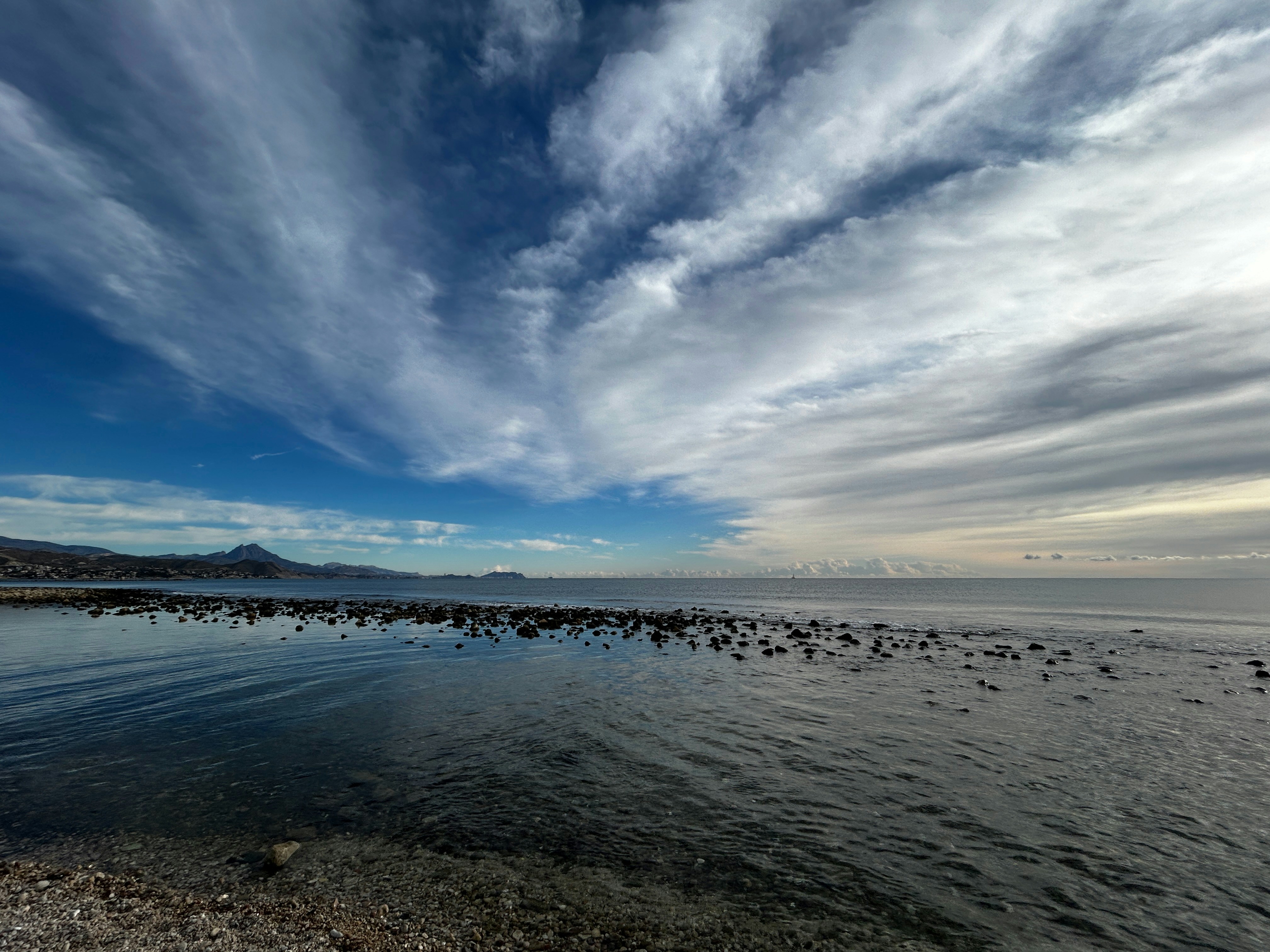 Seaside with beautiful clouds and blue sky with mountains at the background