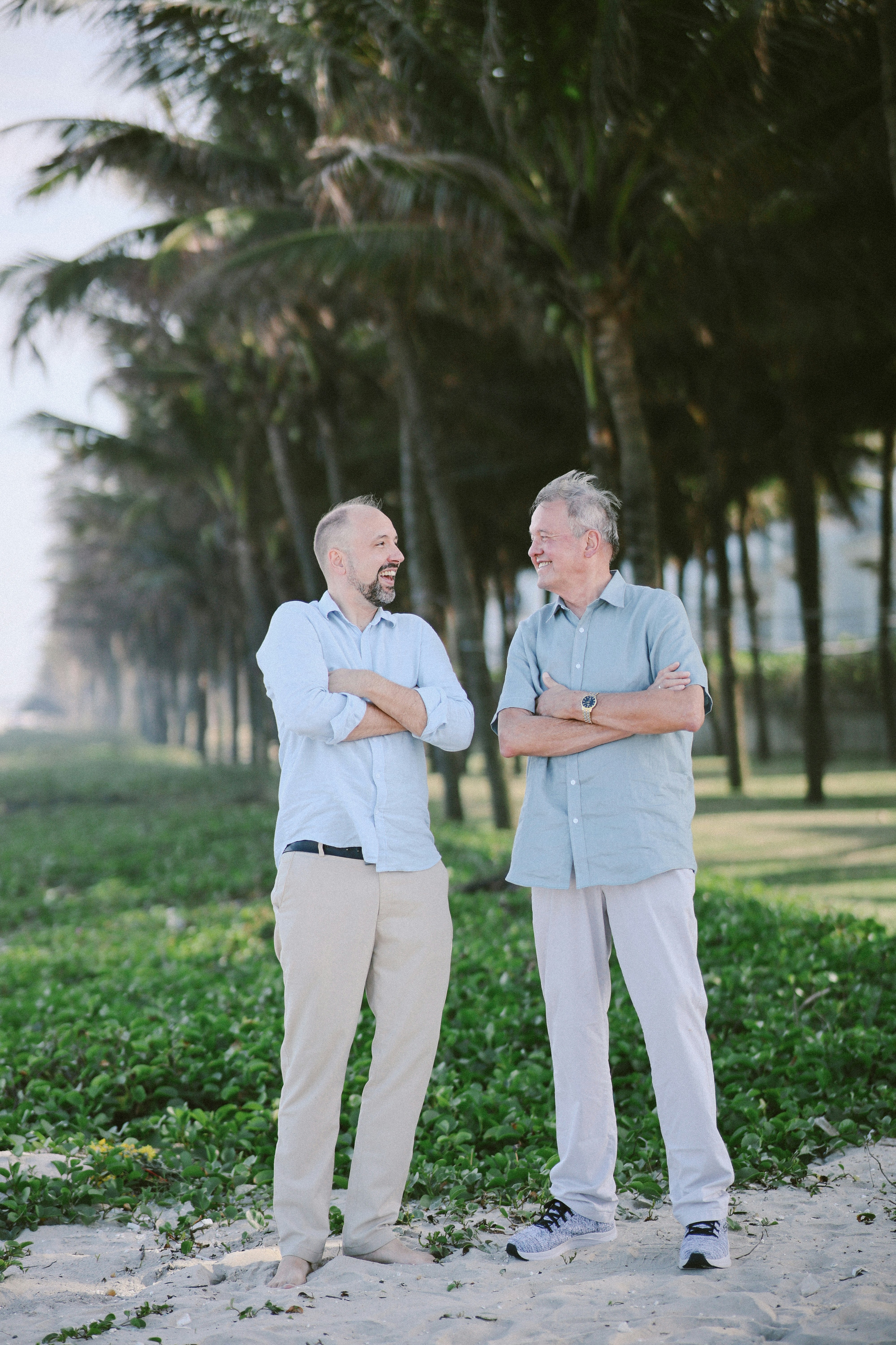 Two friends share a candid moment under a line of palm trees on the beach