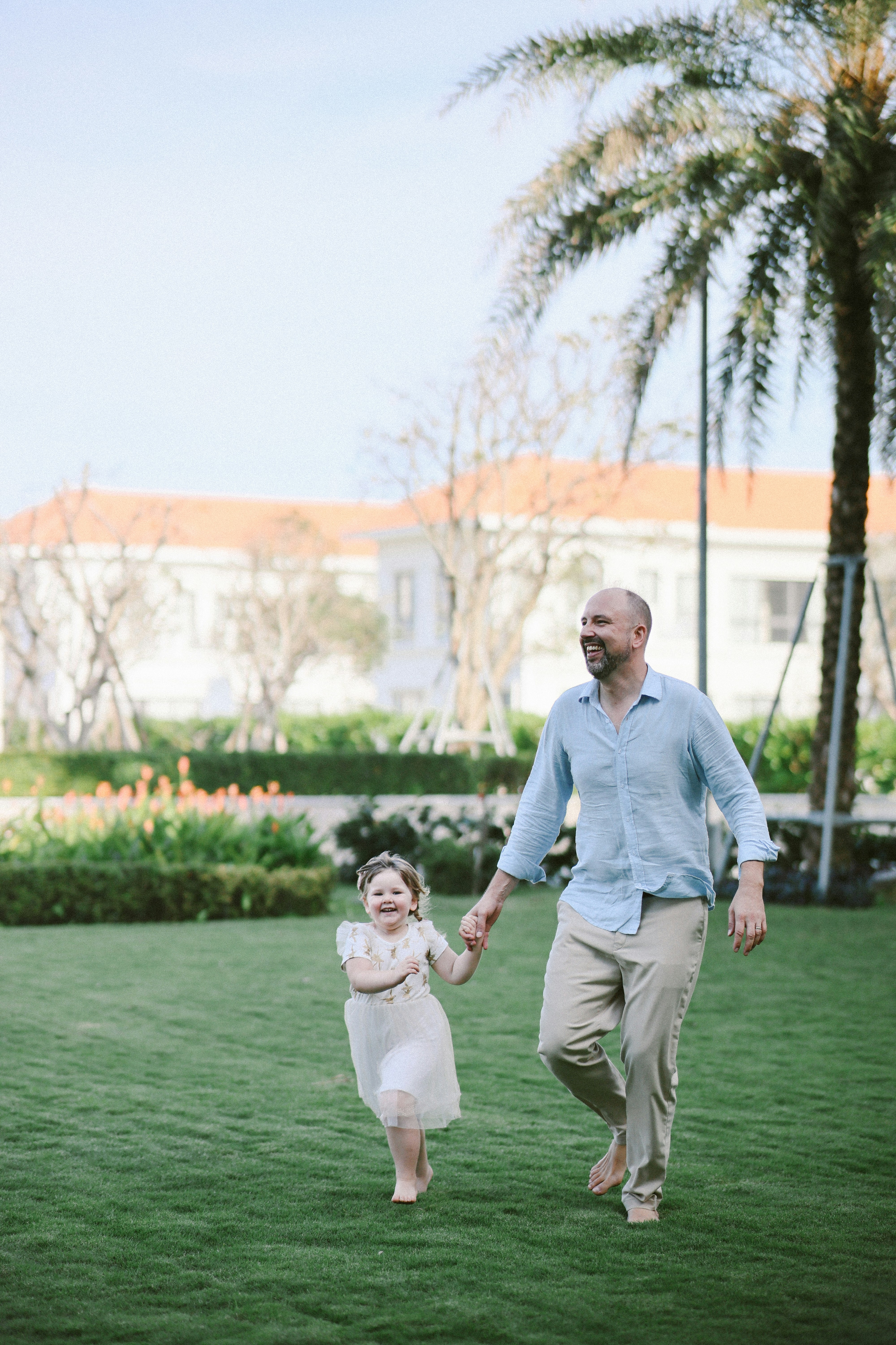 Dad and daughter sprint across a sunlit lawn