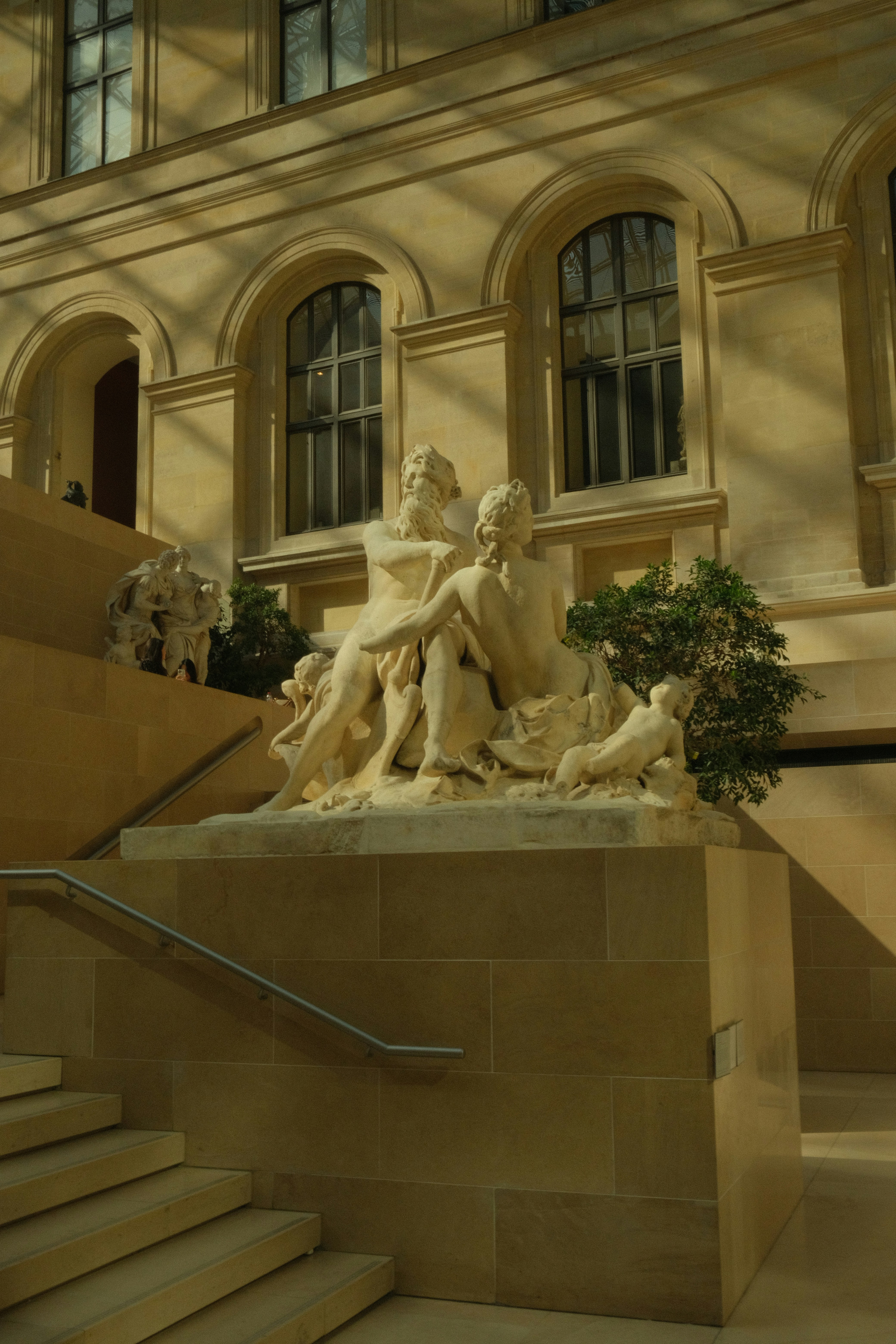 Sculpted figures and sunlit facade overlooking marble stairs