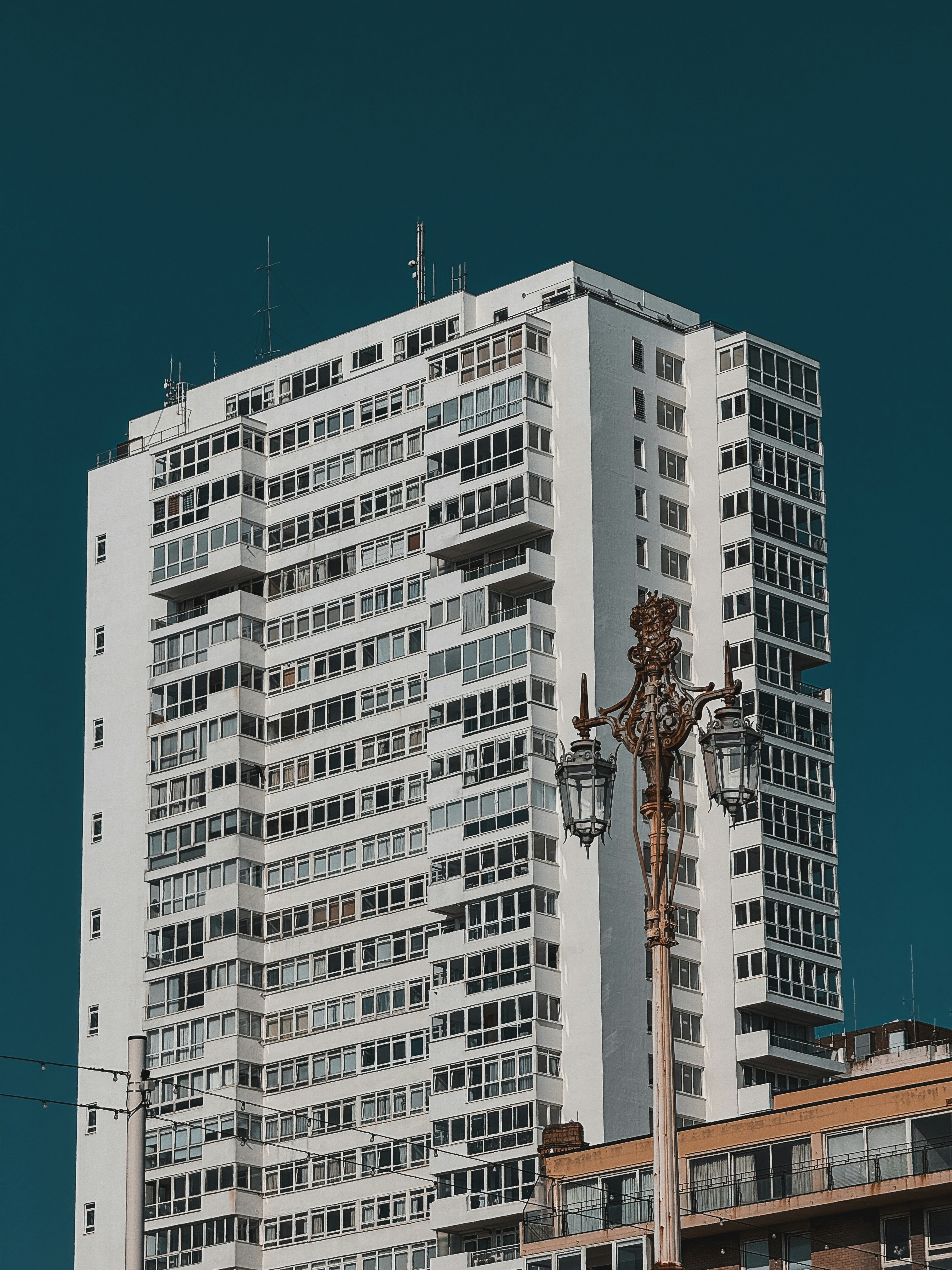 Skyscraper silhouette under a teal sky with ornate street lamp in foreground