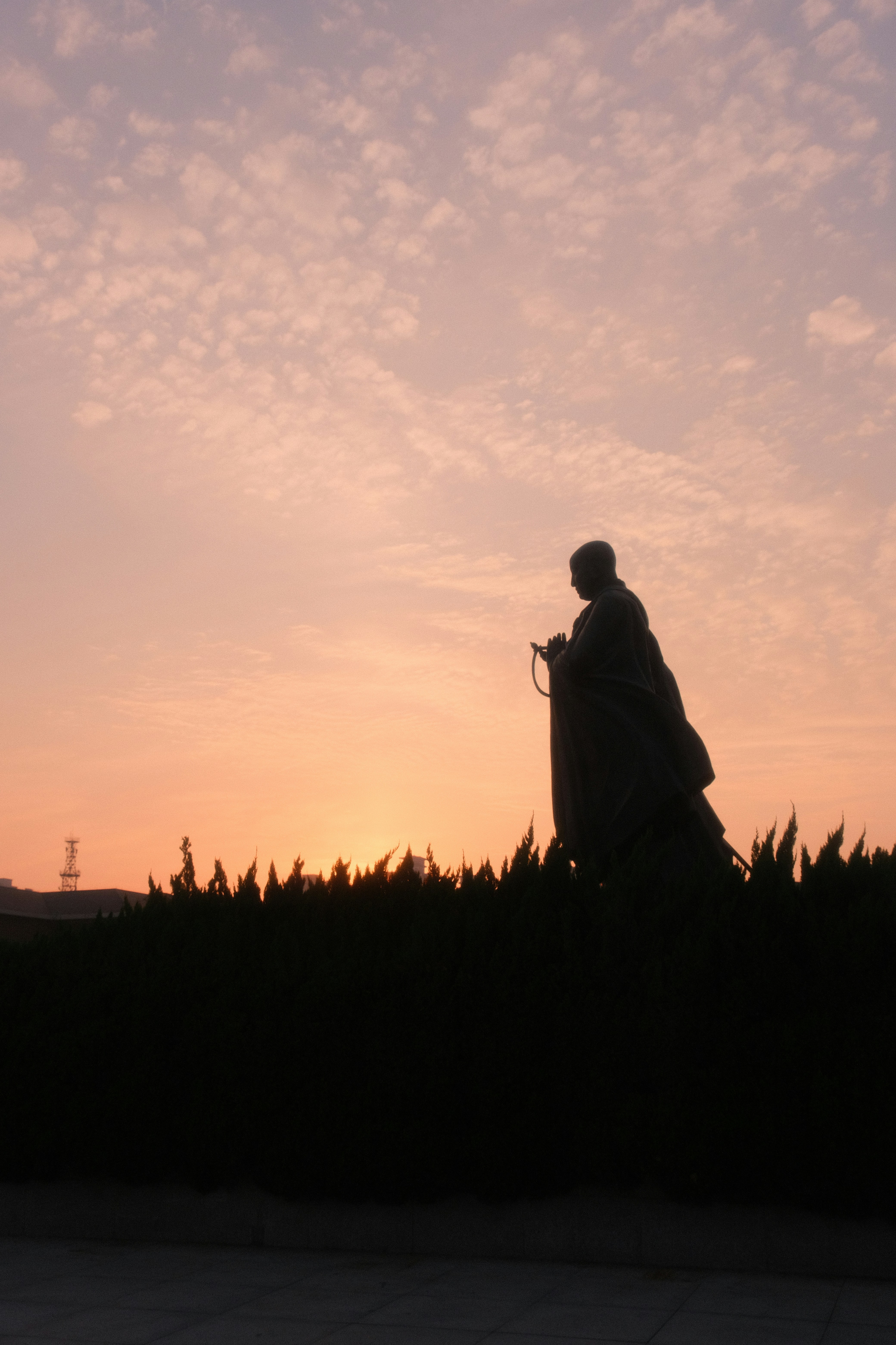Silhouette at Dawn: A photographer atop the hill as soft clouds glow peach