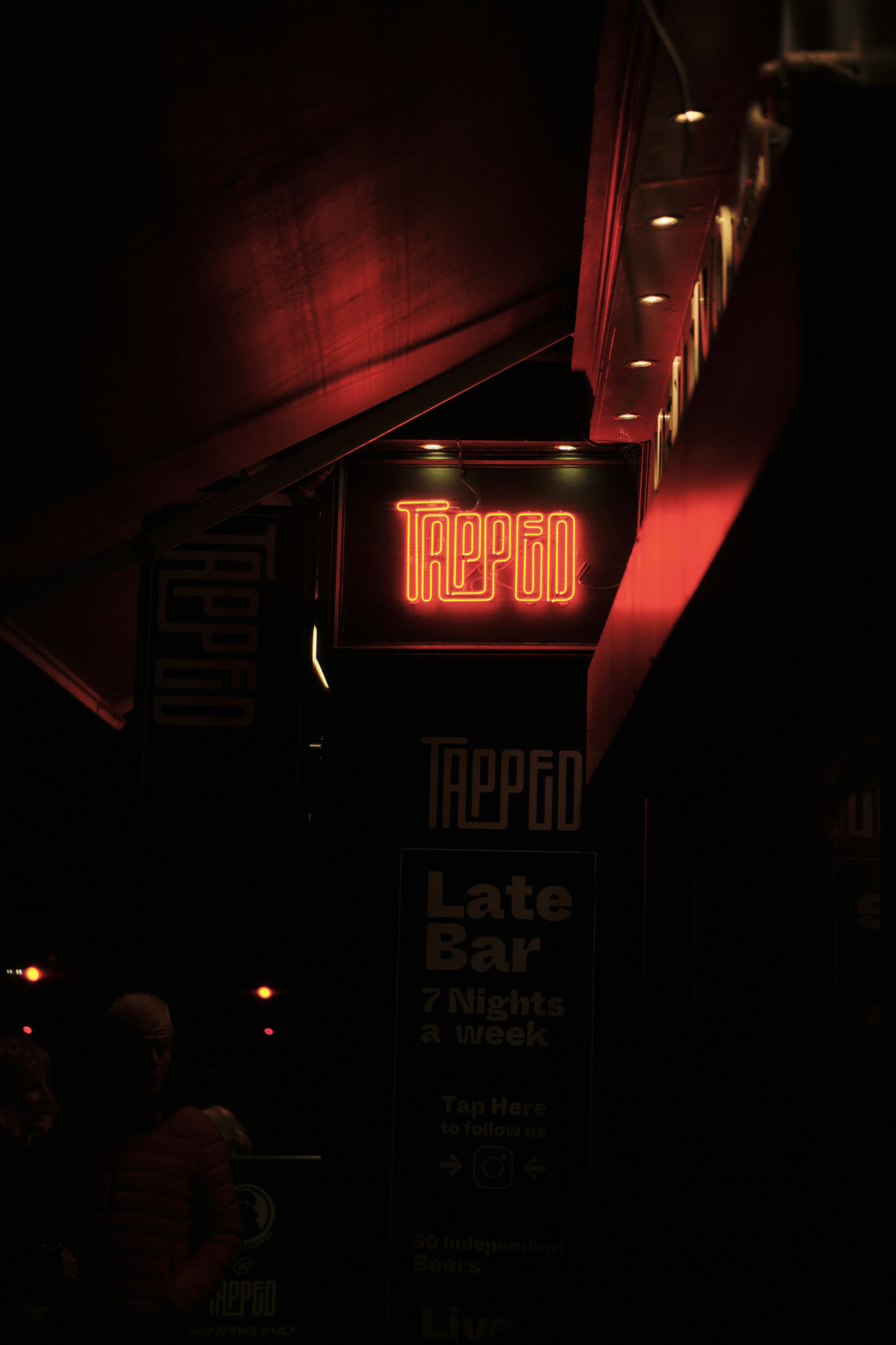 Neon Gate: Red Sign Above a Late-Night Barfront