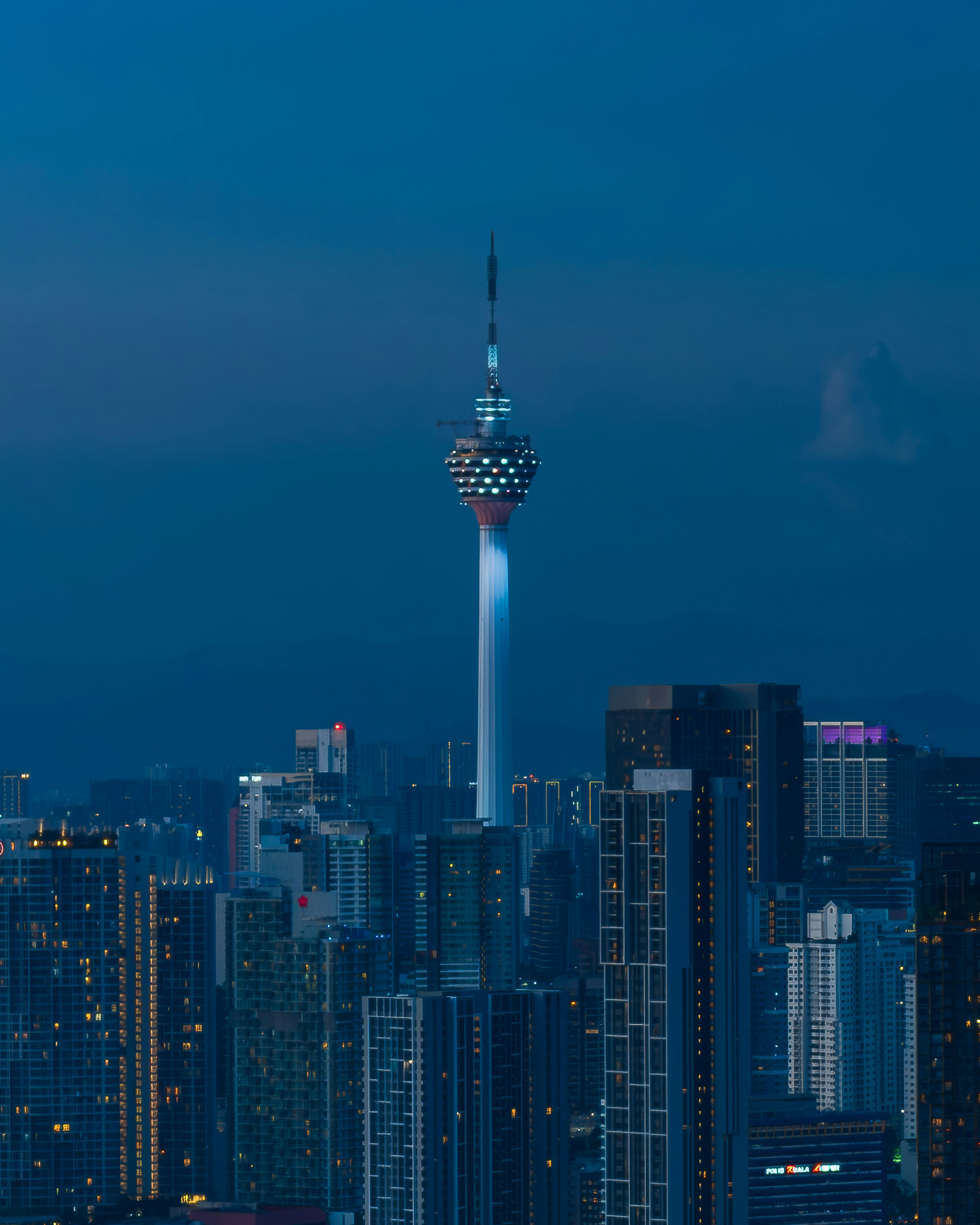 Kuala Lumpur Tower (Menara KL) glows against the dusky sky, standing tall among a sea of high-rises in the heart of Malaysia’s capital.