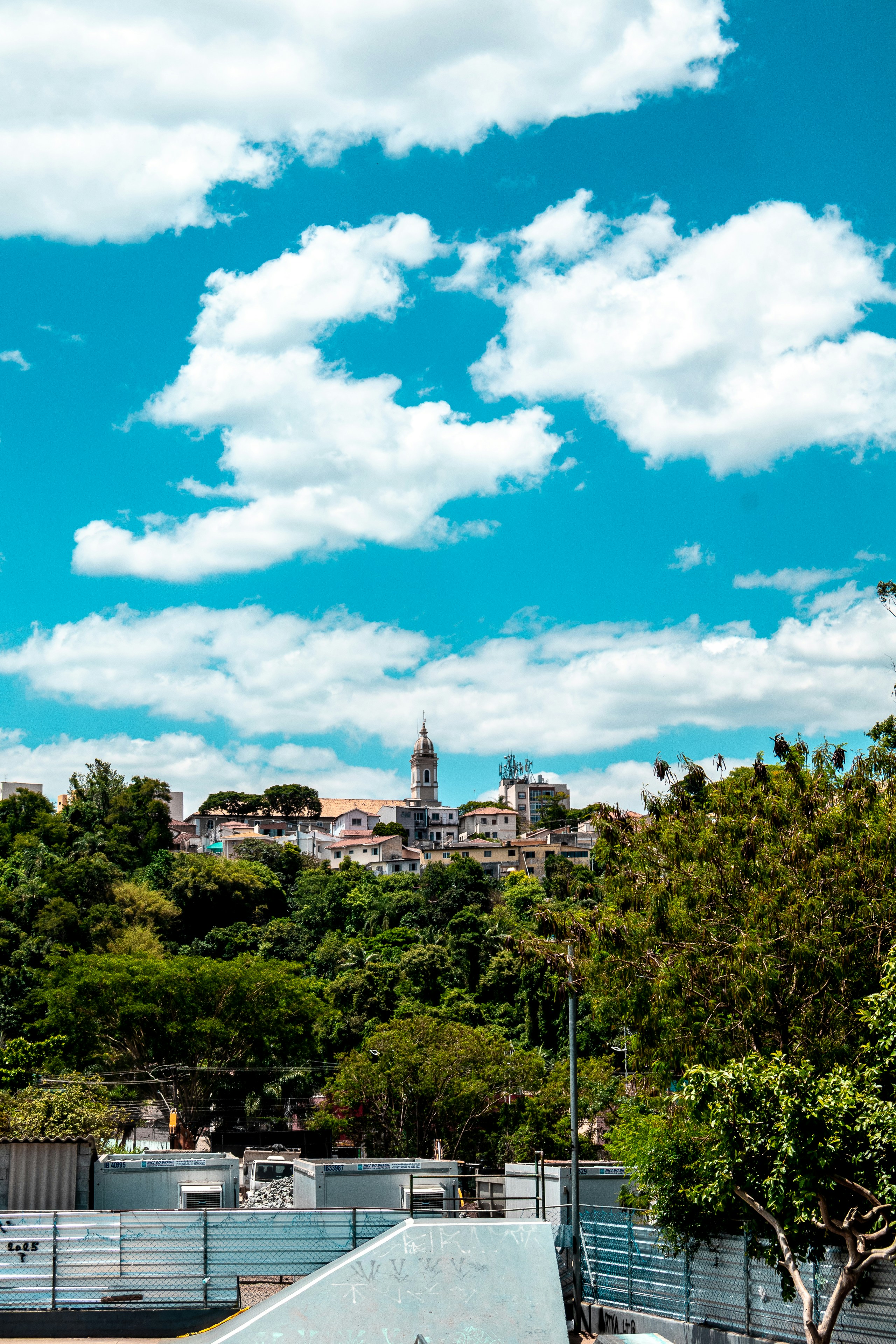 Serene blue sky over a green hill crowned with a church and town.