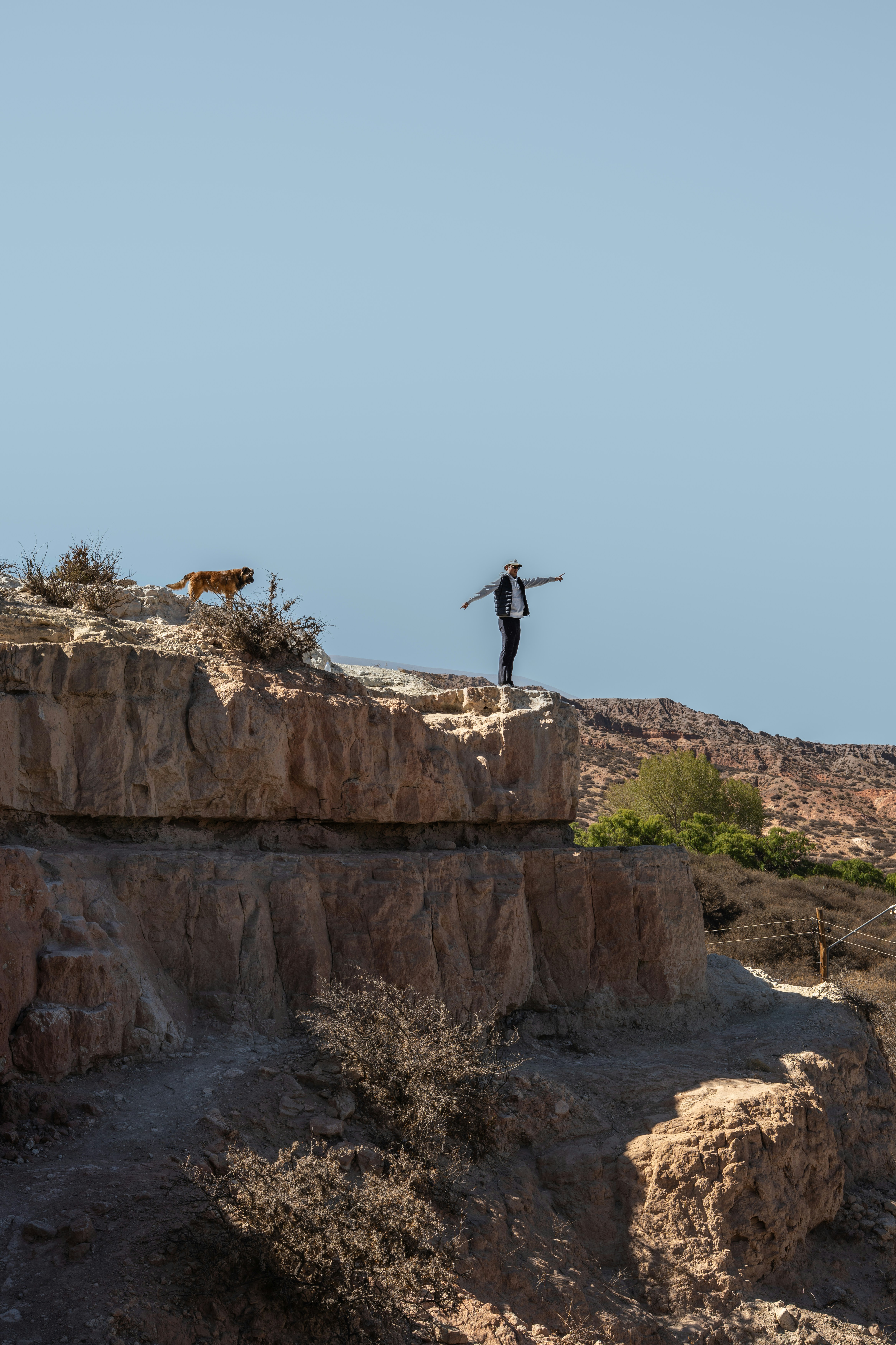 Cliffside Stroll: A Wanderer and a Distant Dog on the Rim
