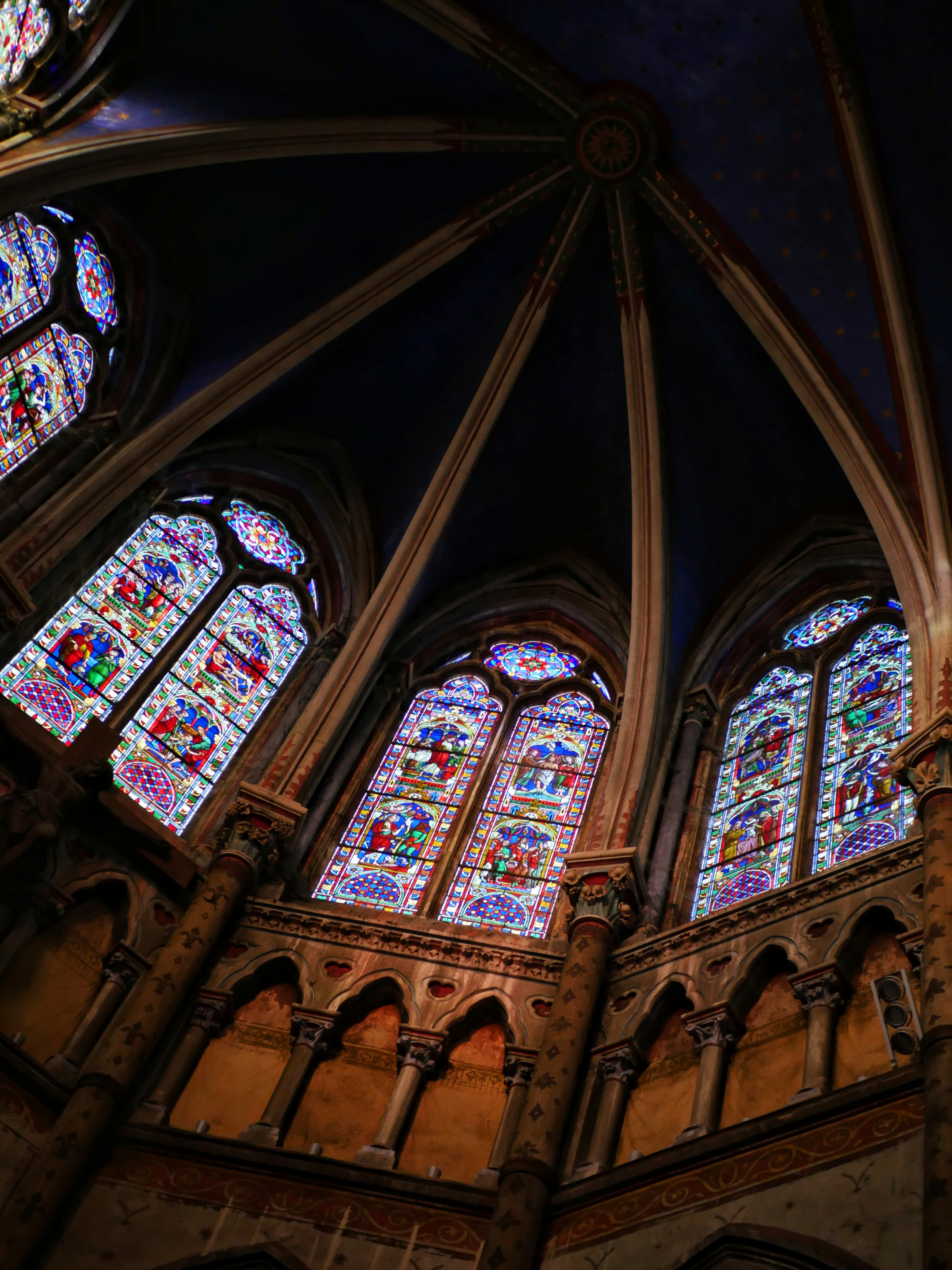 Ornate stained glass windows in a gothic cathedral ceiling.