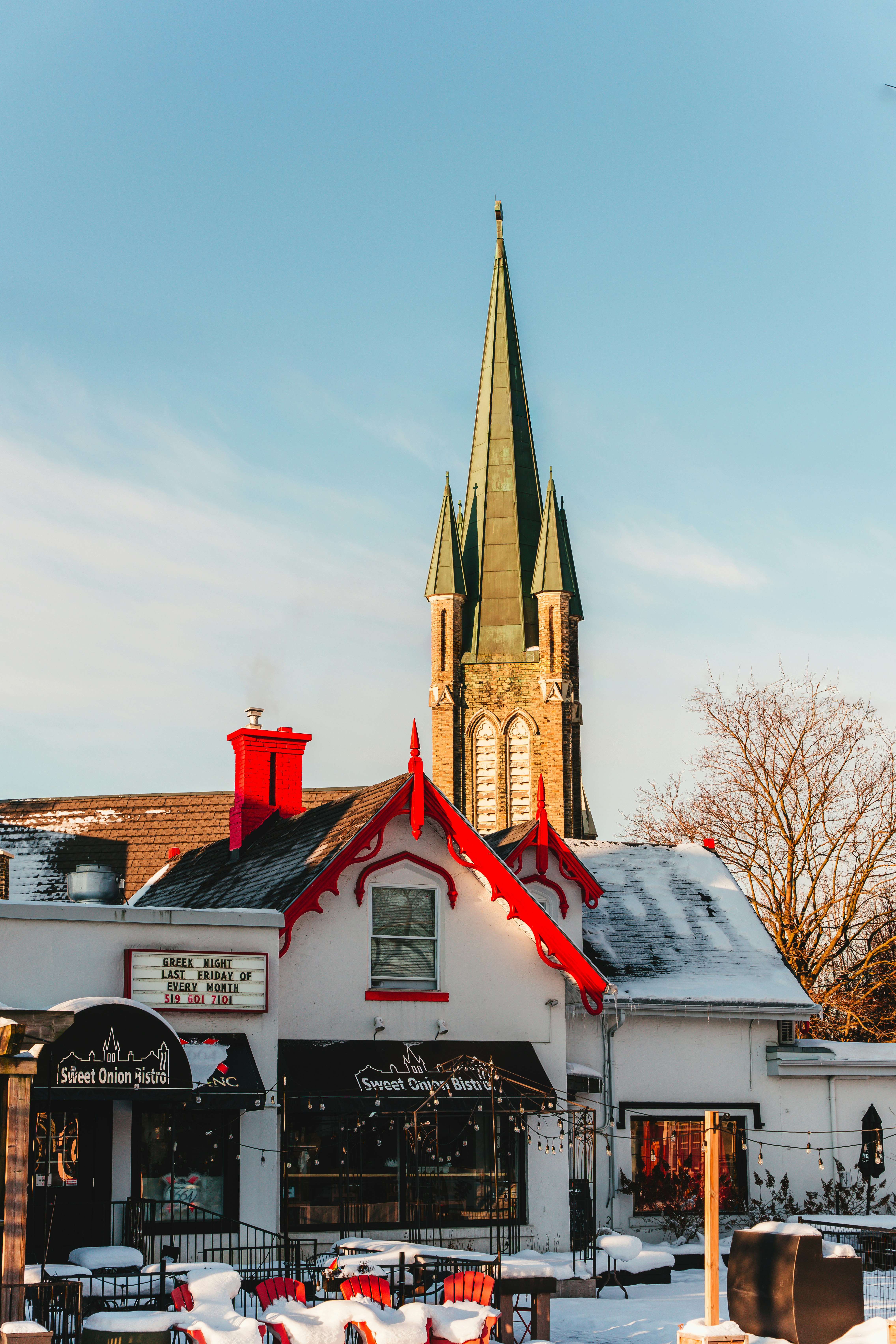 Snow-lit storefronts frame a church spire in late afternoon light
