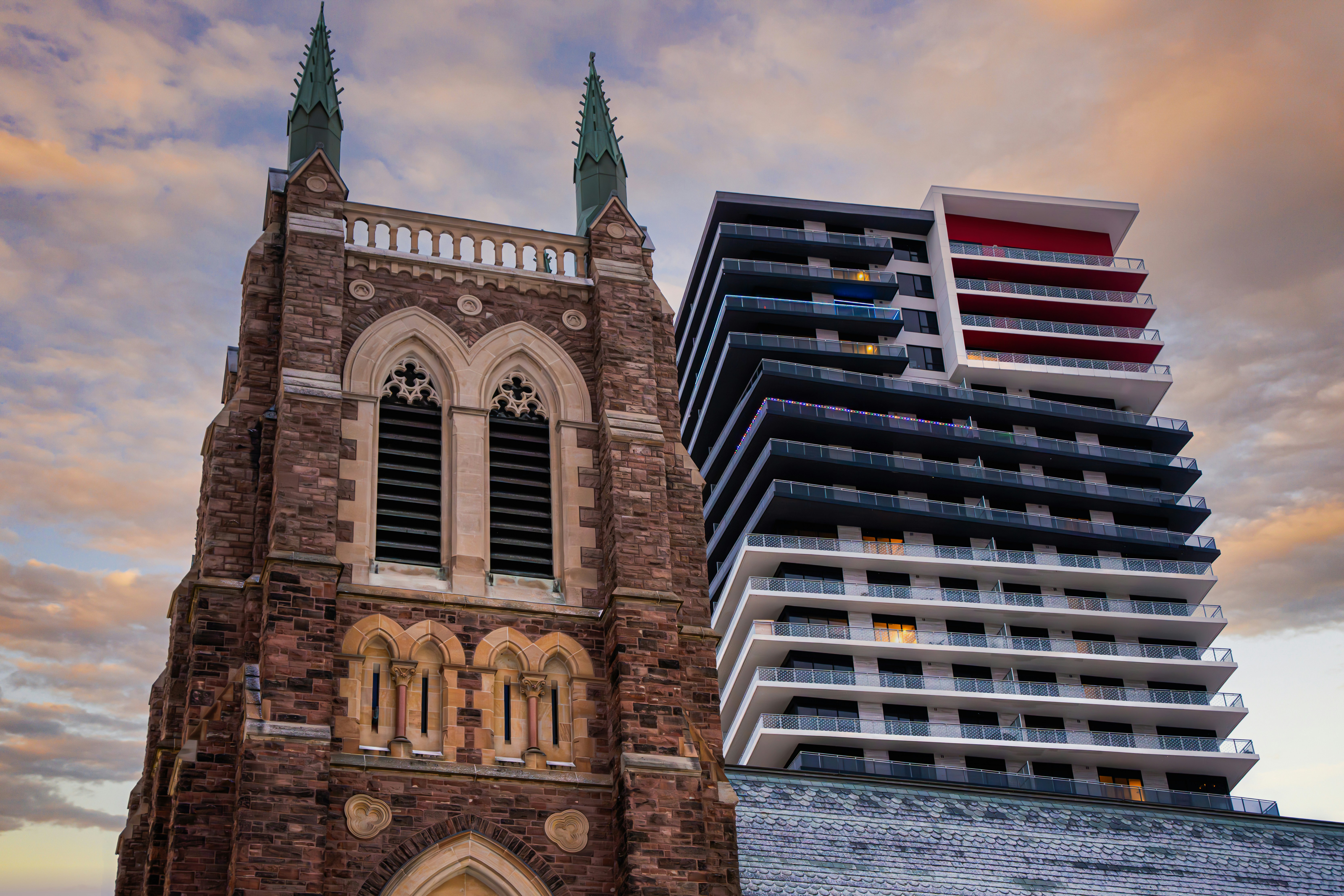 Gothic stone church foreground with stacked modern tower rising behind