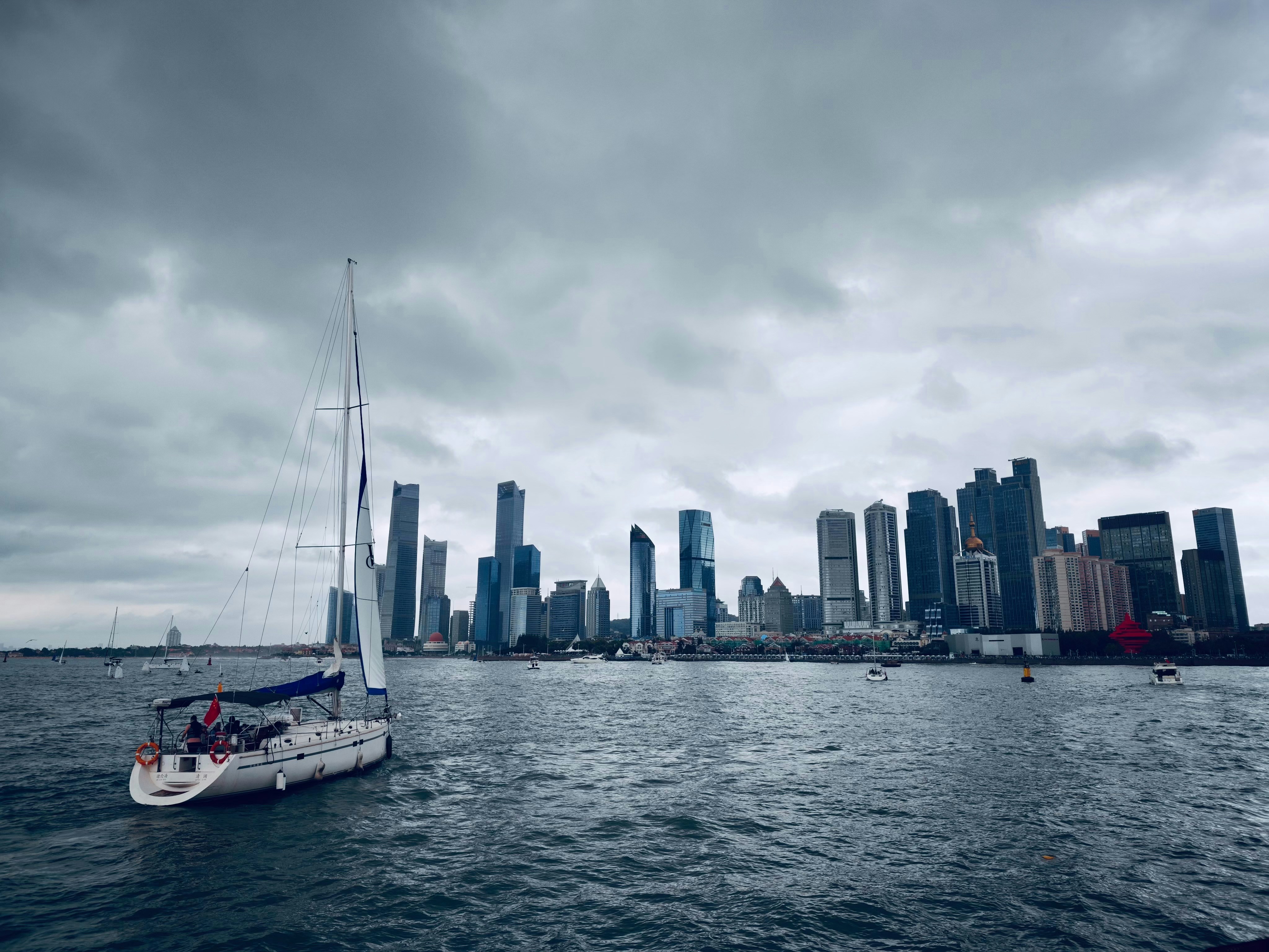 Sailboat in the Shadow of a Modern Harbor Skyline