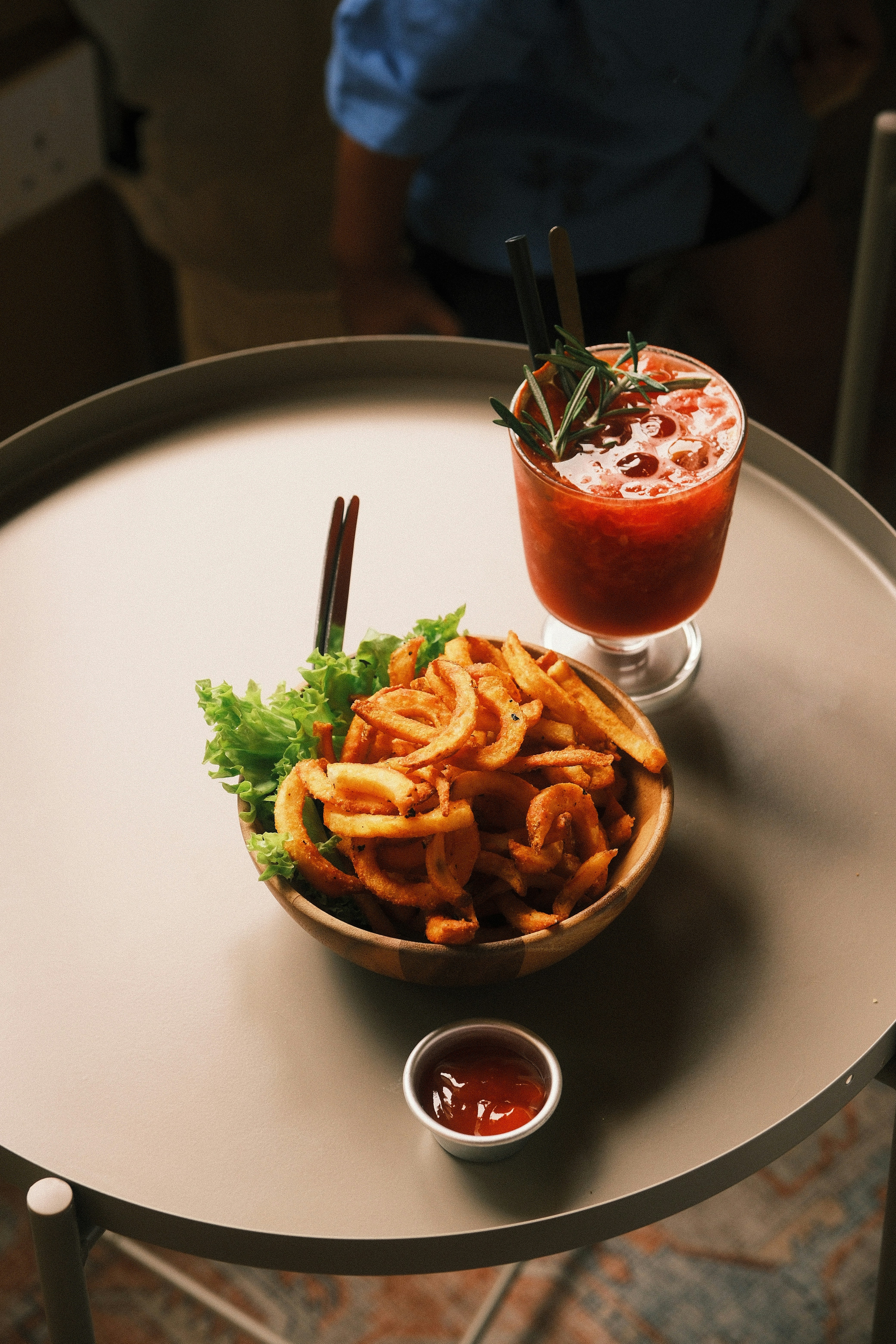 A bowl of crispy curly fries paired with a refreshing drink at Petra Pudu Rooftop Cafe in Pudu, Kuala Lumpur, offering a delightful snack experience with a casual and vibrant atmosphere.