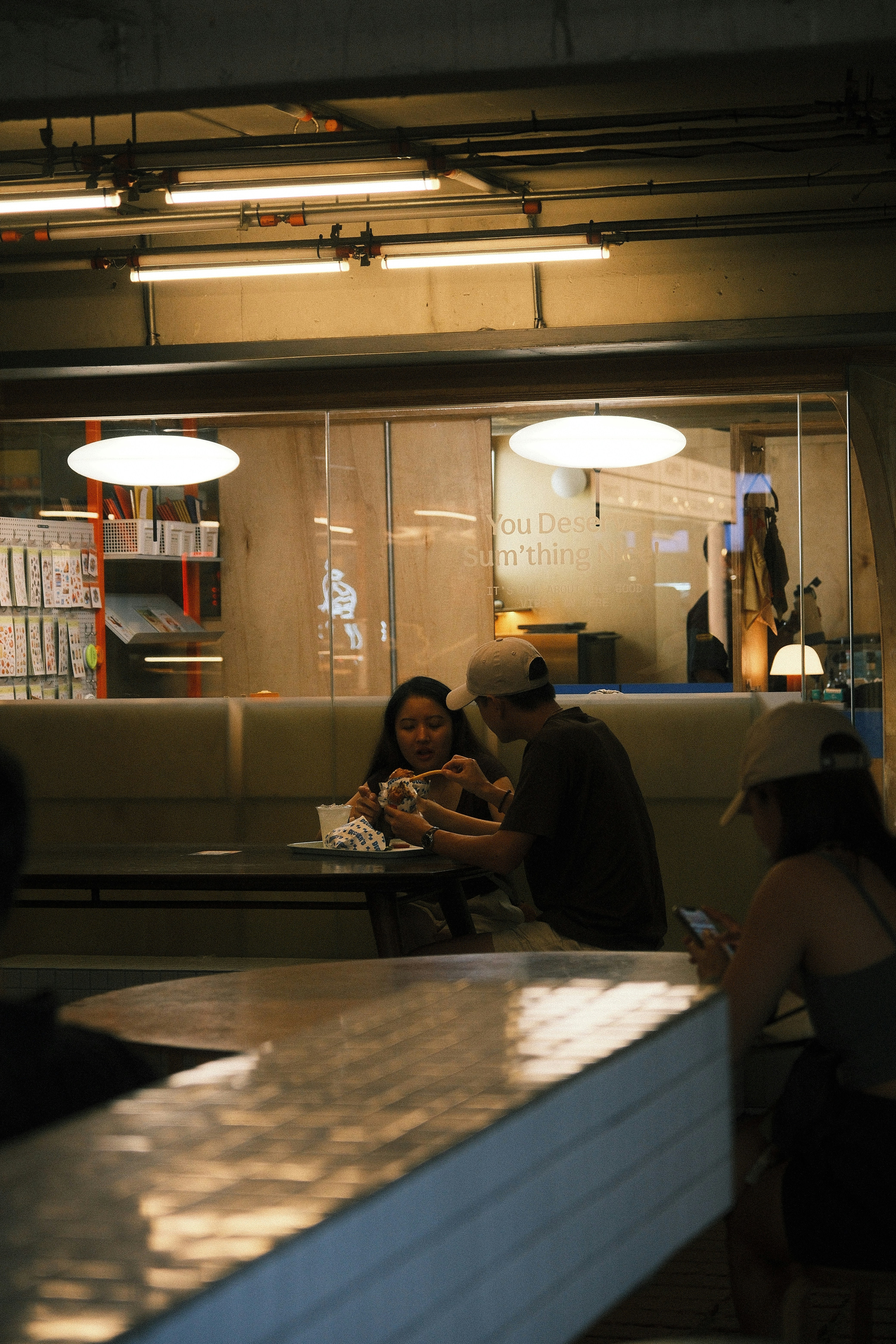 A cozy and modern cafe inside REXKL, Kuala Lumpur, where people enjoy dining and socializing. The cafe's contemporary design and ambiance make it a popular spot for casual hangouts.